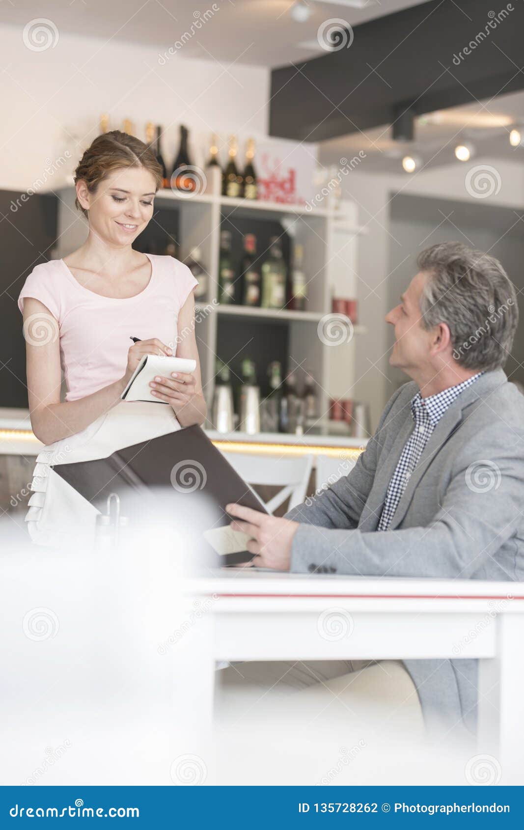 Young Waitress Taking Order from Mature Customer at Restaurant Stock ...