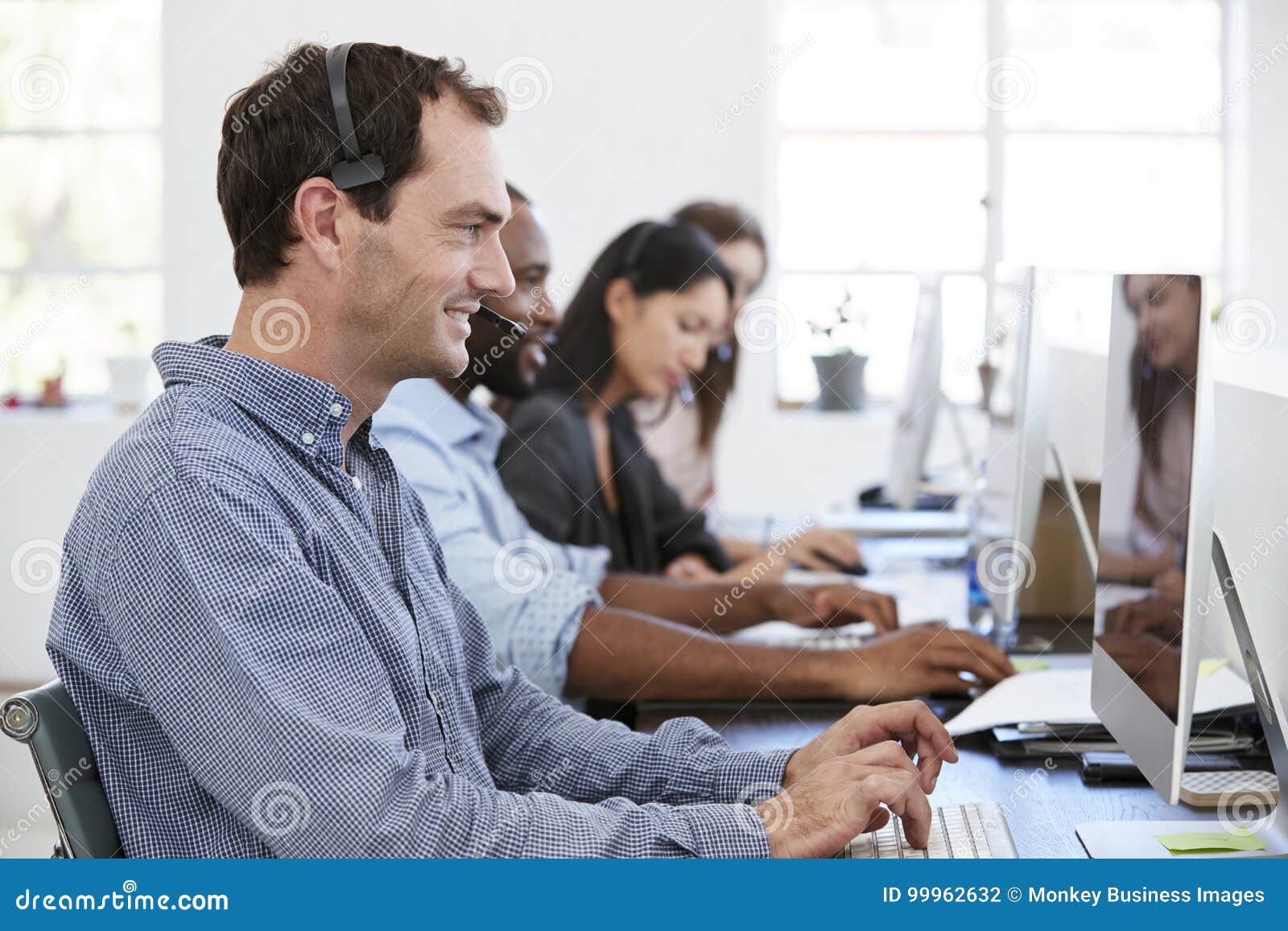 Young White Man with Headset Working at Computer in Office Stock Photo ...