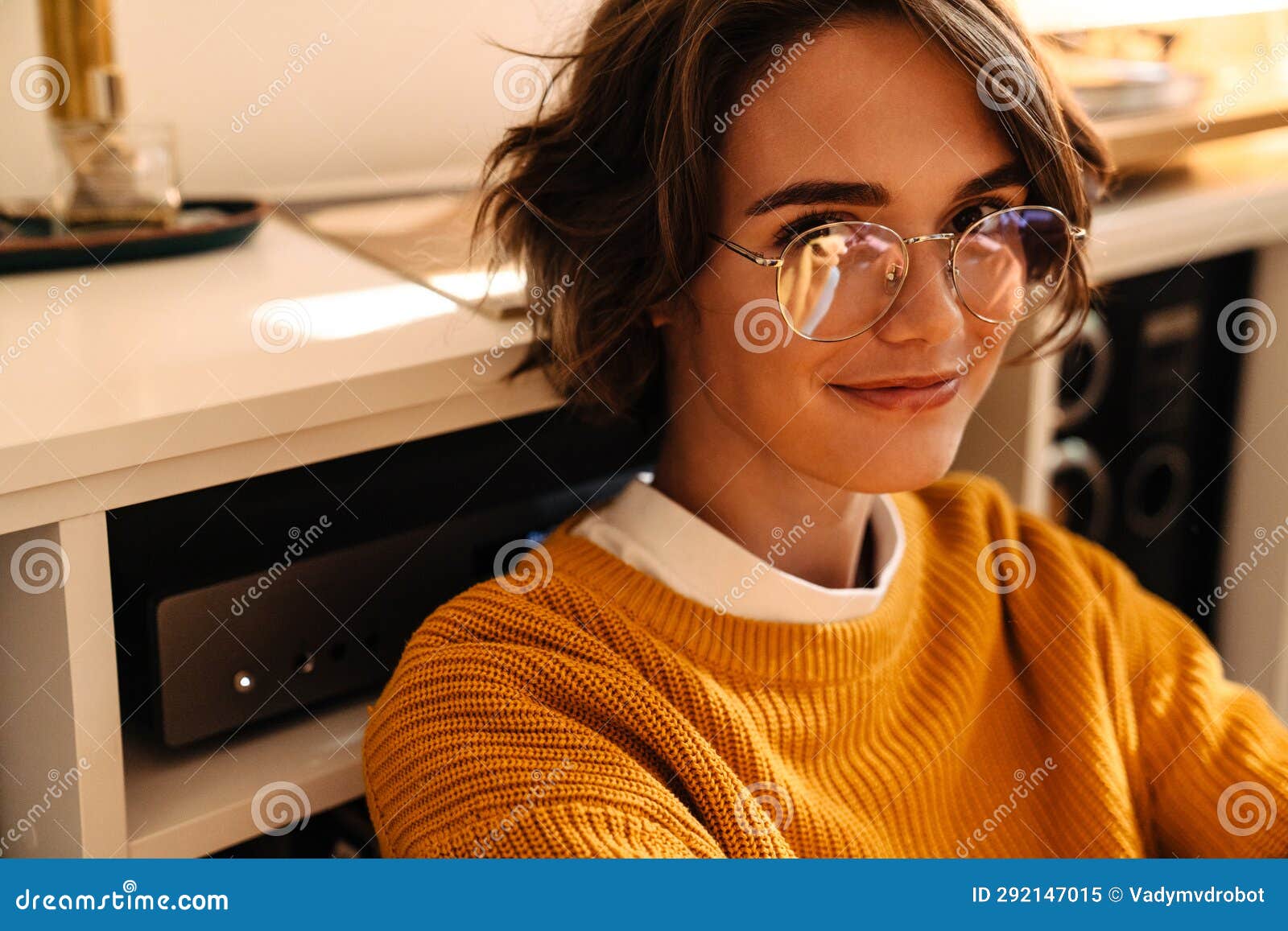 Young White Woman In Eyeglasses Smiling While Sitting On Floor Stock