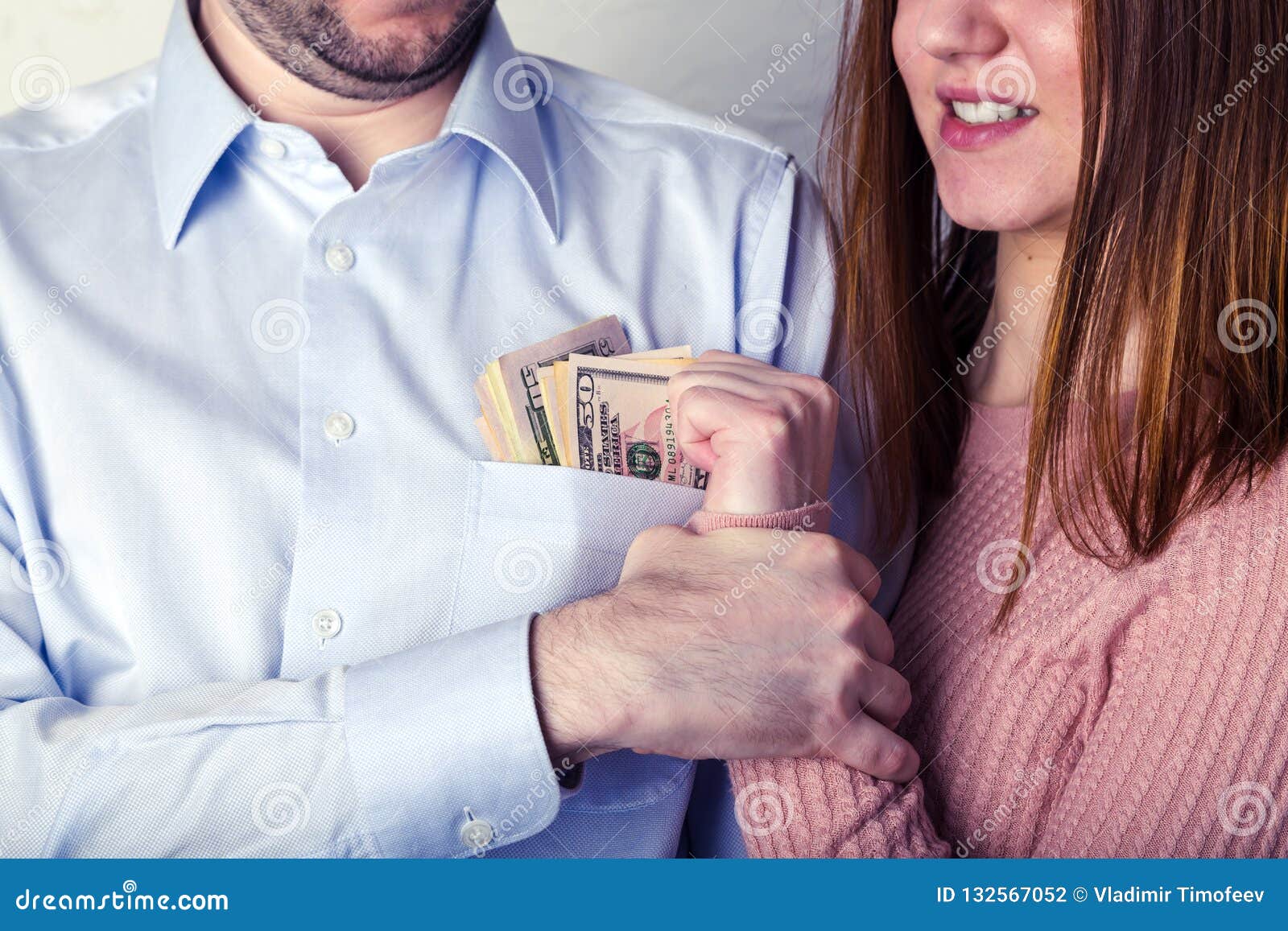 Young Wife Pulls Out Dollar Bills From Her Husband`s Shirt Pocket The