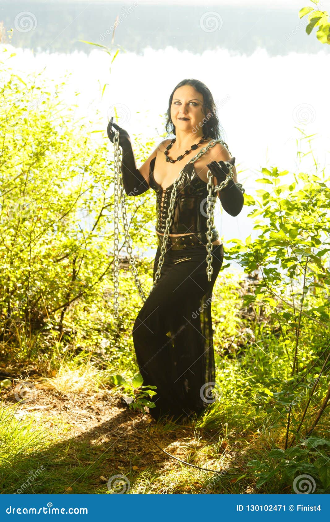 A Young Witch in Black Clothes with Chains in the Hands of a Forest ...