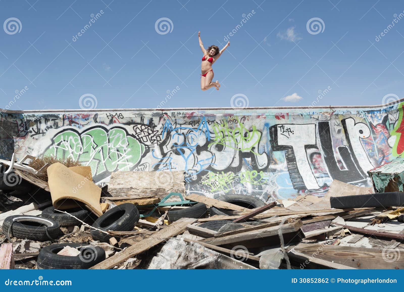 Young Woman in Bikini Jumping Over Graffiti Wall with Garbage in ...
