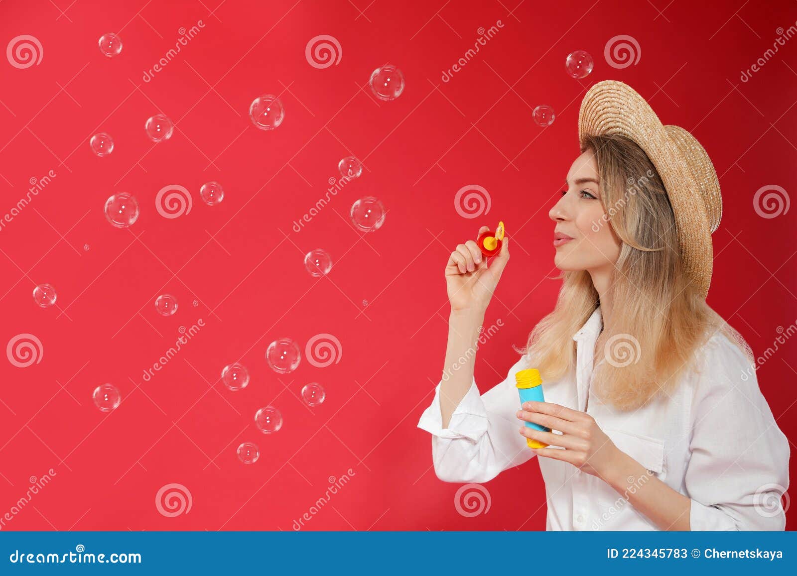 Young Woman Blowing Soap Bubbles On Red Space For Text Stock Image