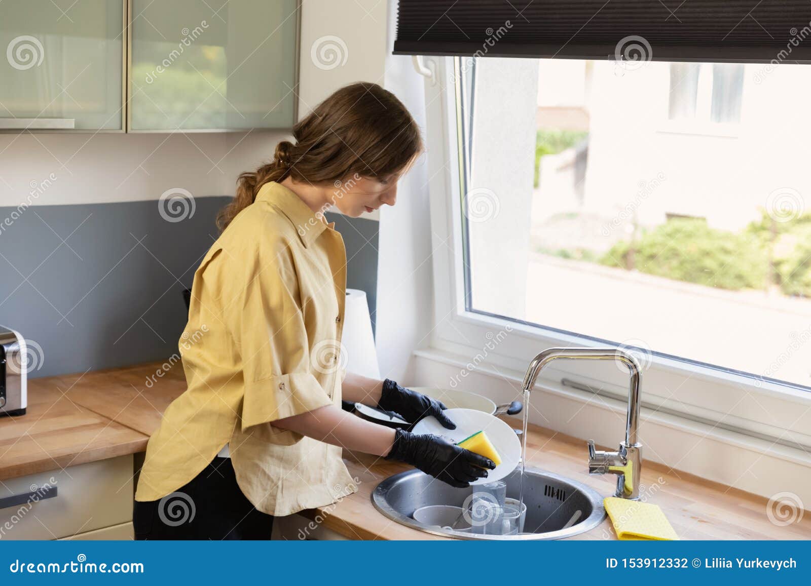 A Young Woman Cleans Up in the Kitchen, Washing Dishes. Stock Photo ... A Young Woman Cleans Up in the Kitchen, Washing Dishes. Stock Photo ...