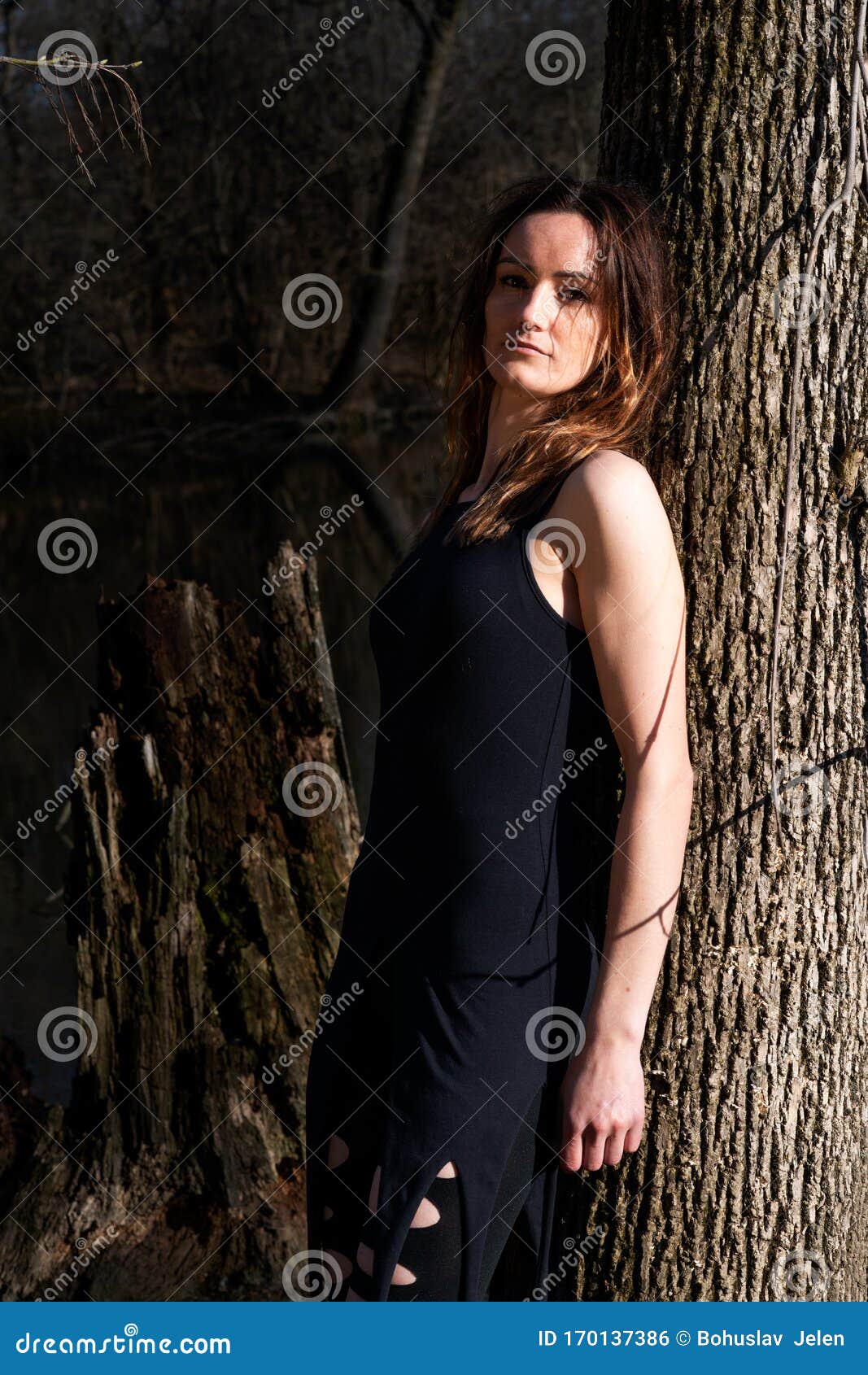 Young Woman With Dark Long Hair In Black Robes Is Leaning Against The