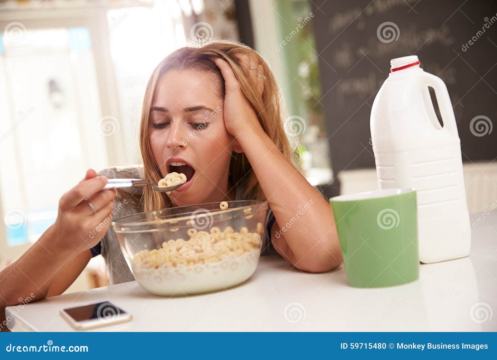 Young Woman Eating Breakfast Whilst Using Mobile Phone Stock Photo ...