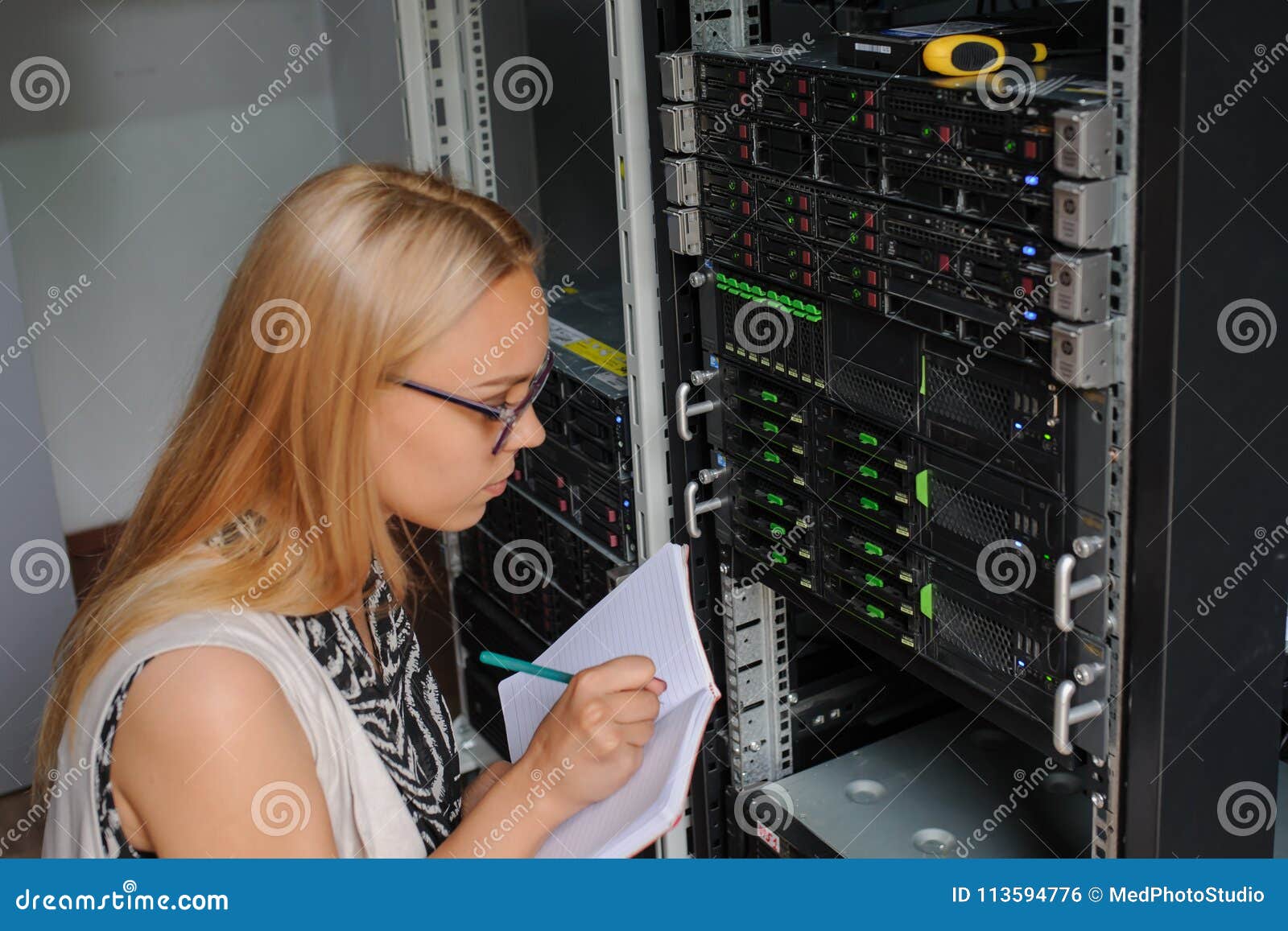 Young Woman Engineer it between the Server Racks in the Data Center ...