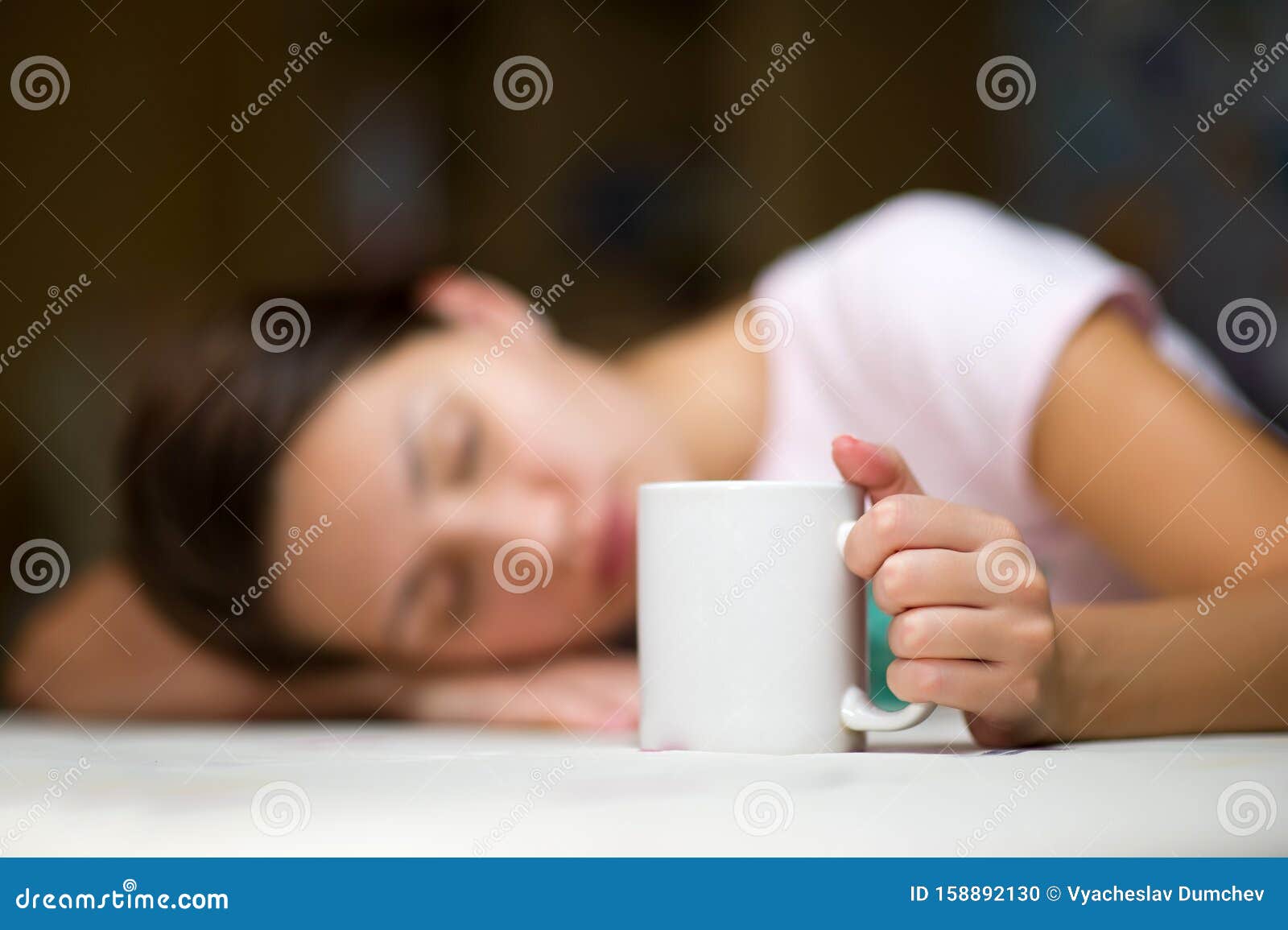 Young Woman Fell Asleep at the Table Holding a White Cup of Coffee ... Young Woman Fell Asleep at the Table Holding a White Cup of Coffee ...