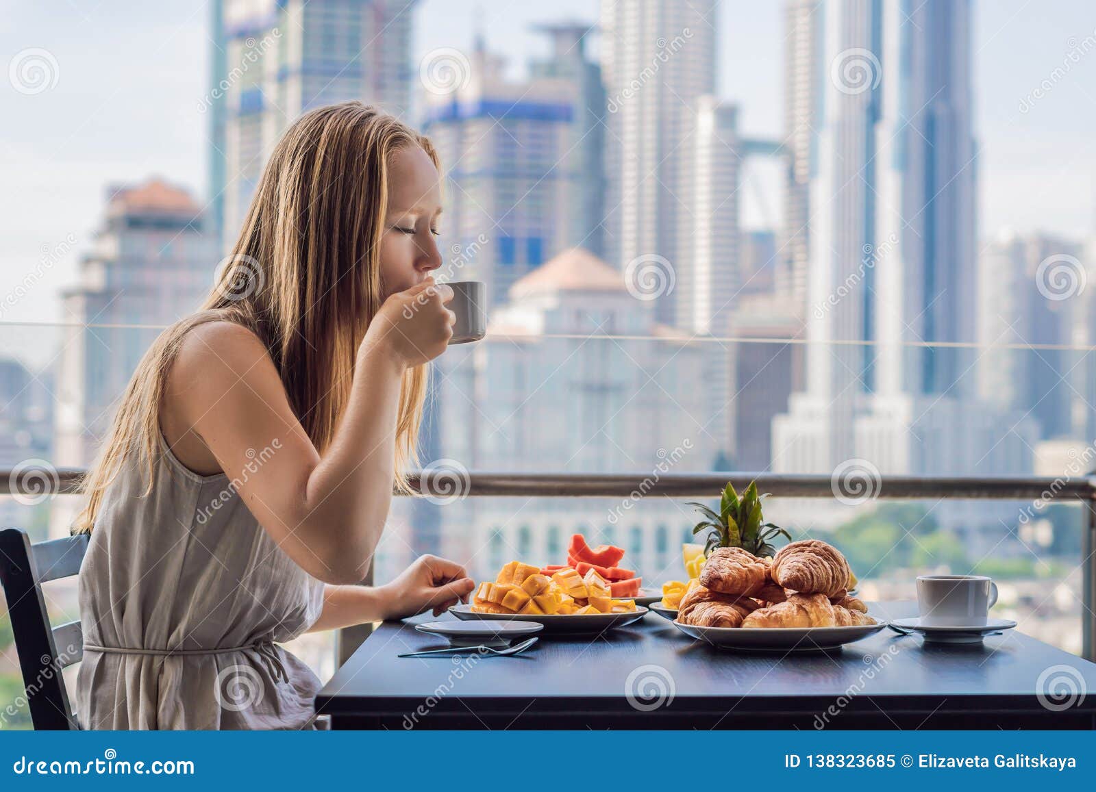 A Young Woman Is Having Breakfast On The Balcony Breakfast Table With