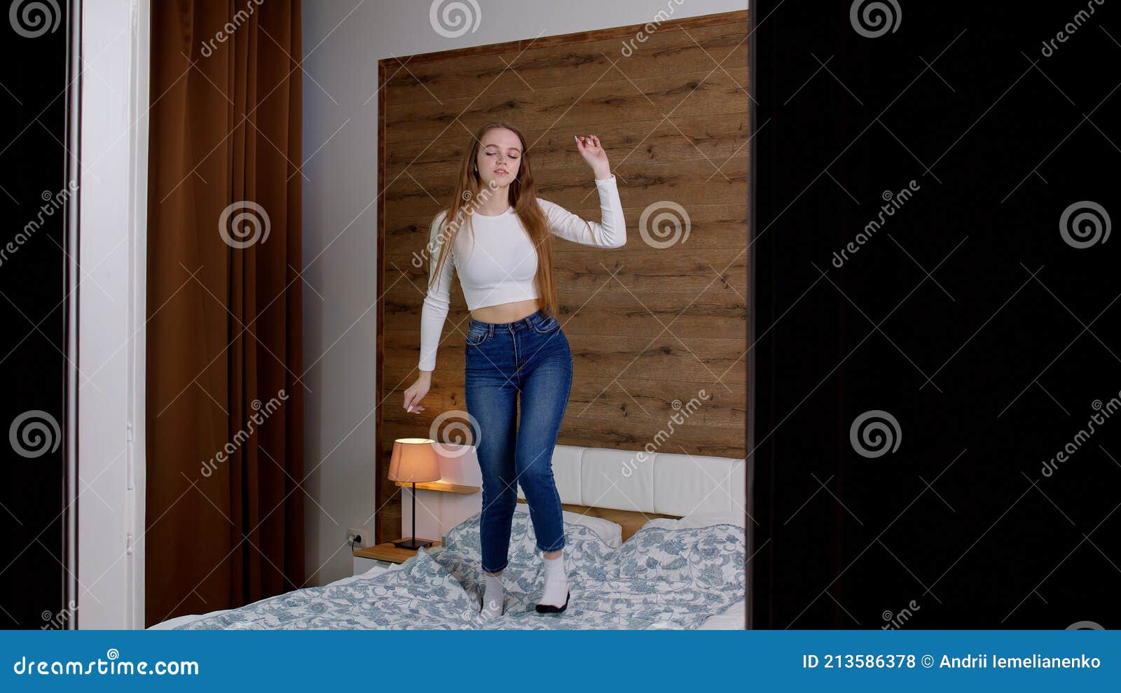 Young Woman Having Fun Dancing On Bed At Home Bedroom Listening Music