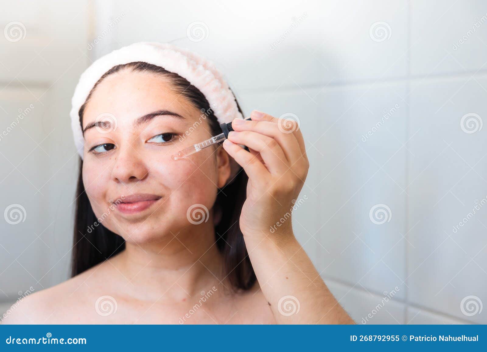 Young Woman On The Mirror Applying Serum Collagen And Hyaluronic Acid