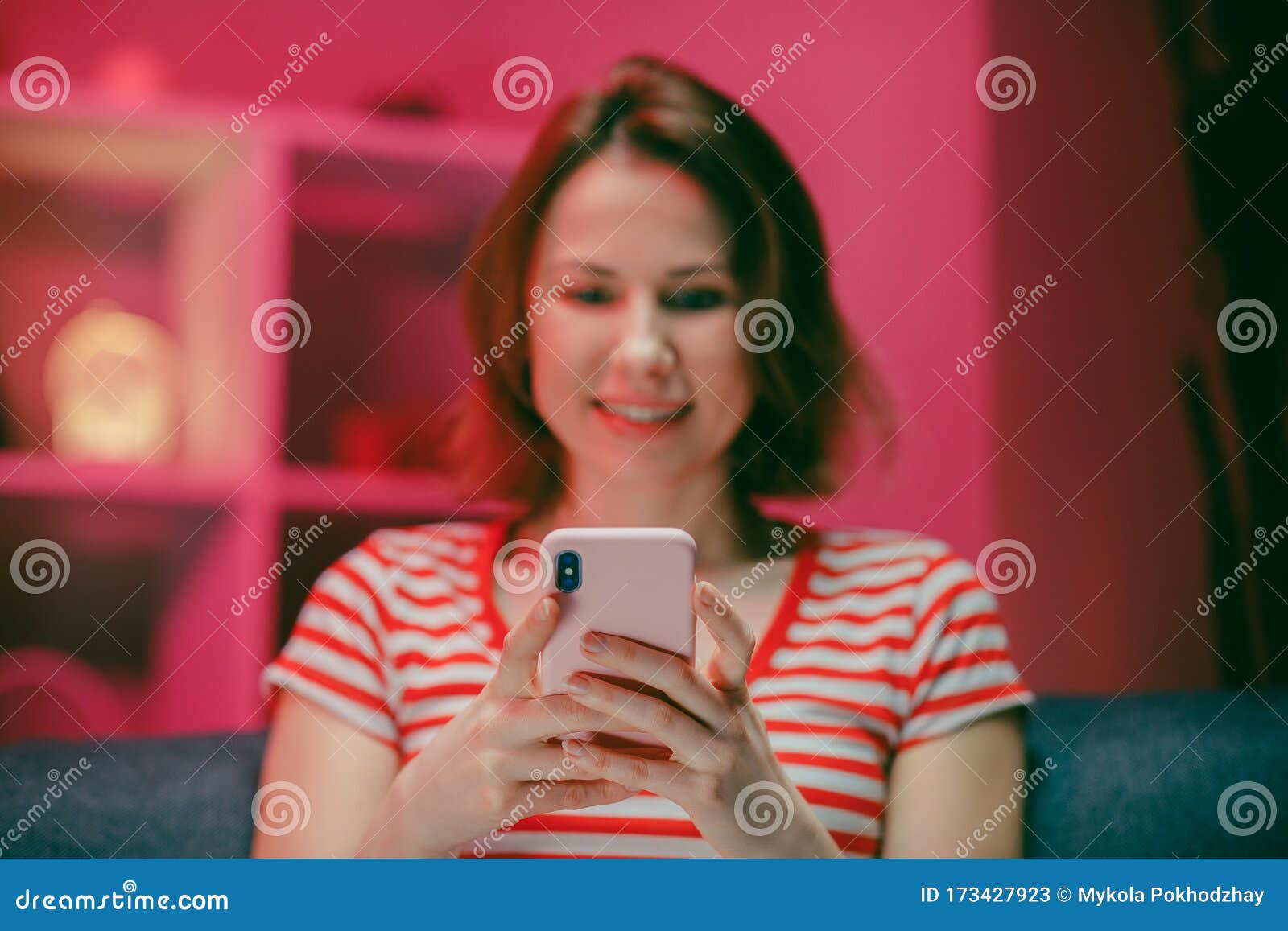 Young Woman Holding Smart Phone Looking At Cellphone Screen Laughing