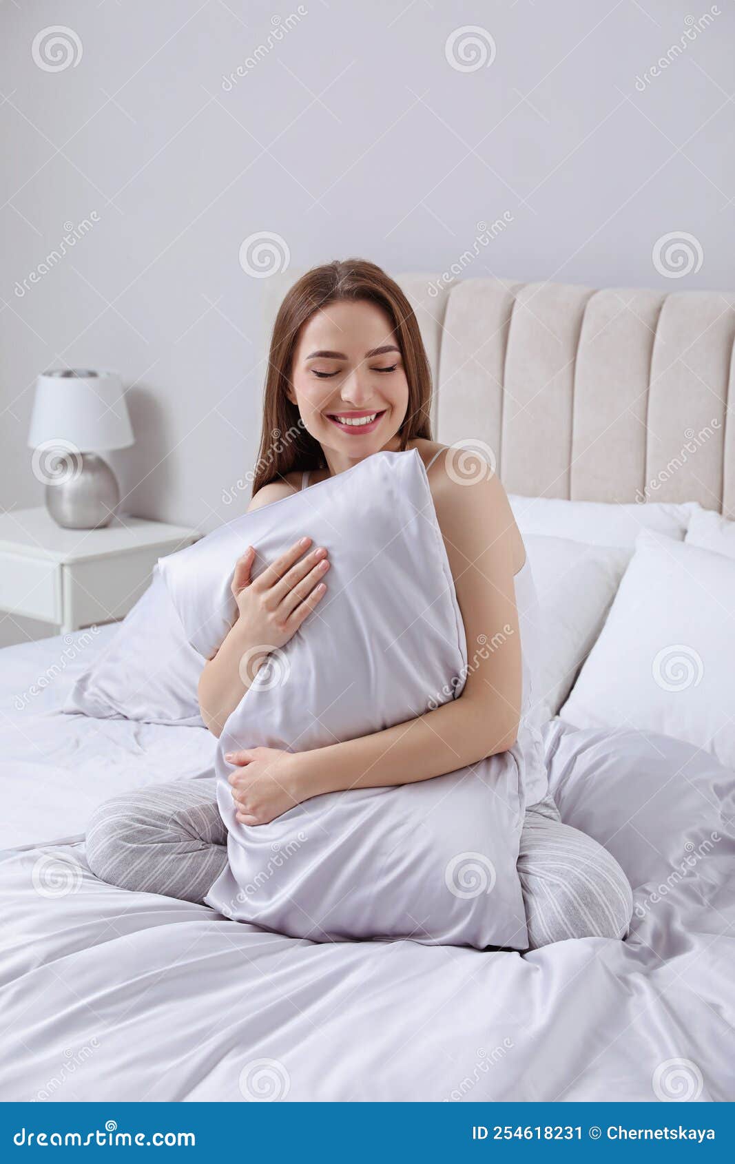 Young Woman Hugging Pillow on Bed with Silky Linens Stock Image - Image ...