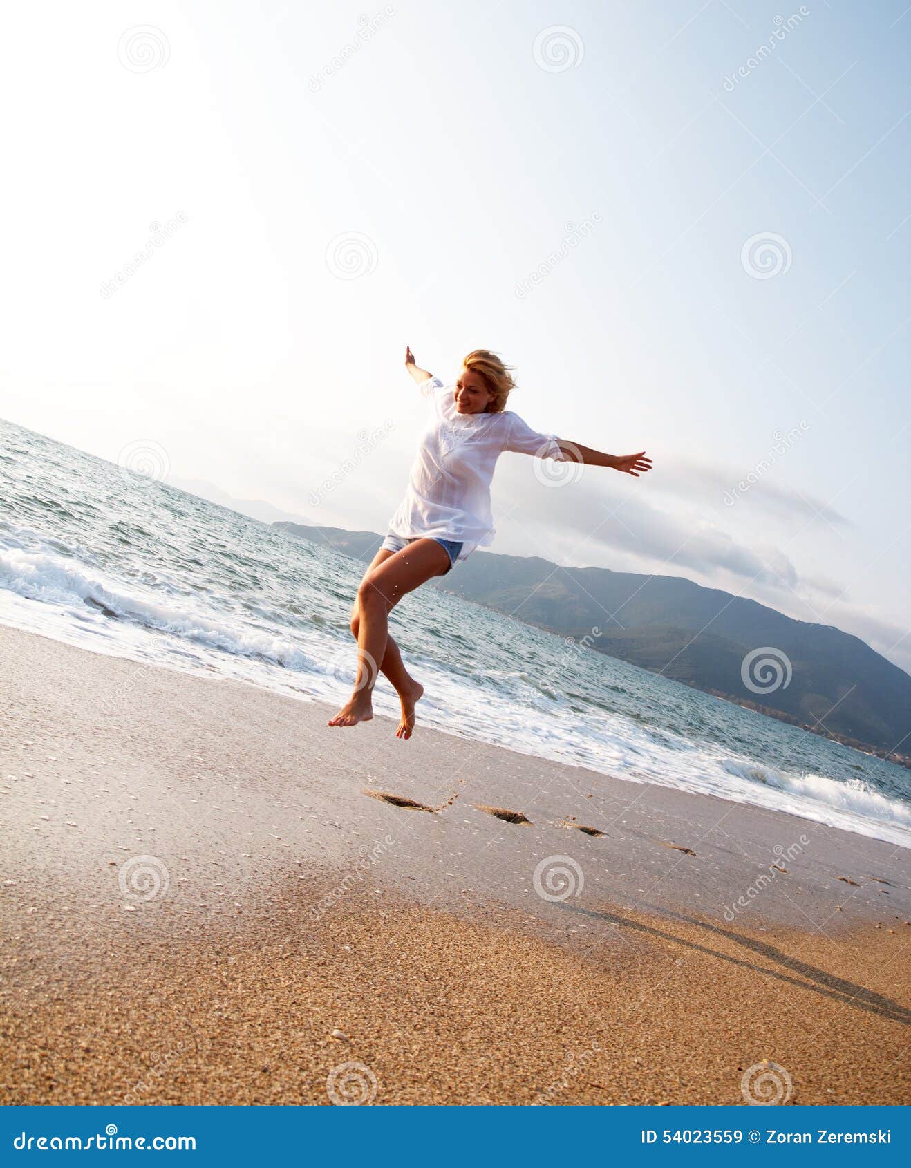 Young Woman Jumping with Hands Raised on Beach Stock Image - Image of ...