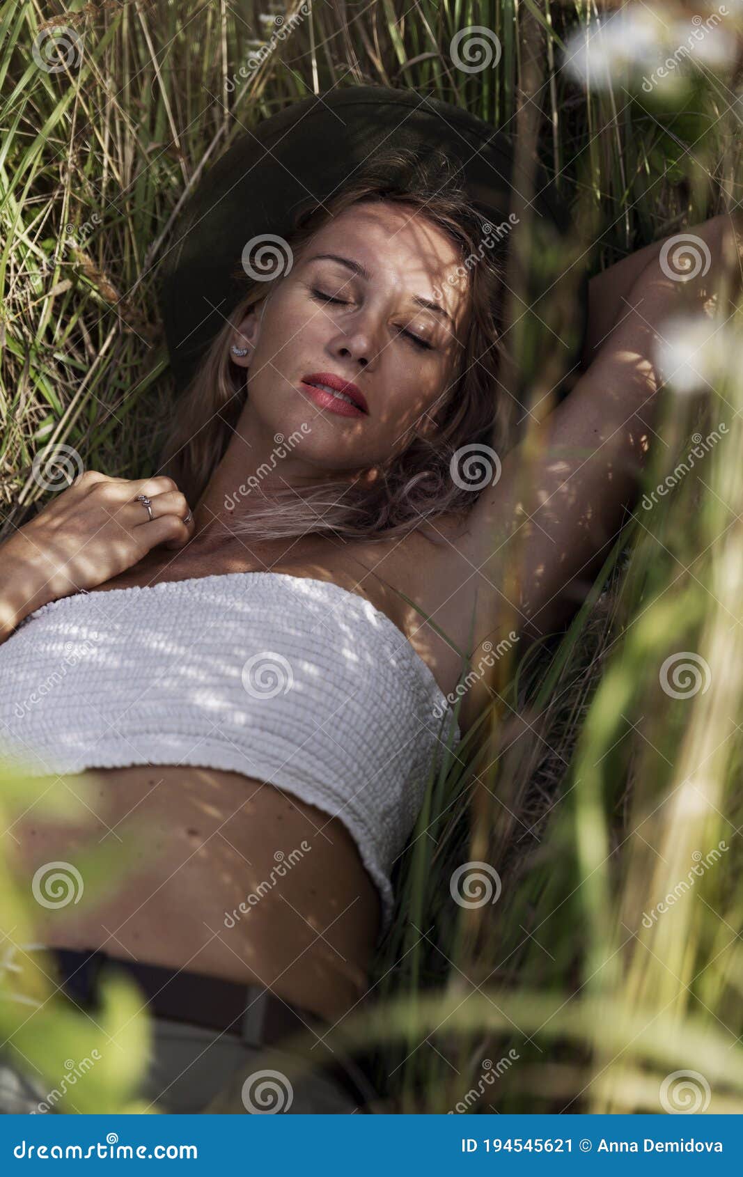 Young Woman Lies With Closed Eyes In Tall Grass In A Field Summer