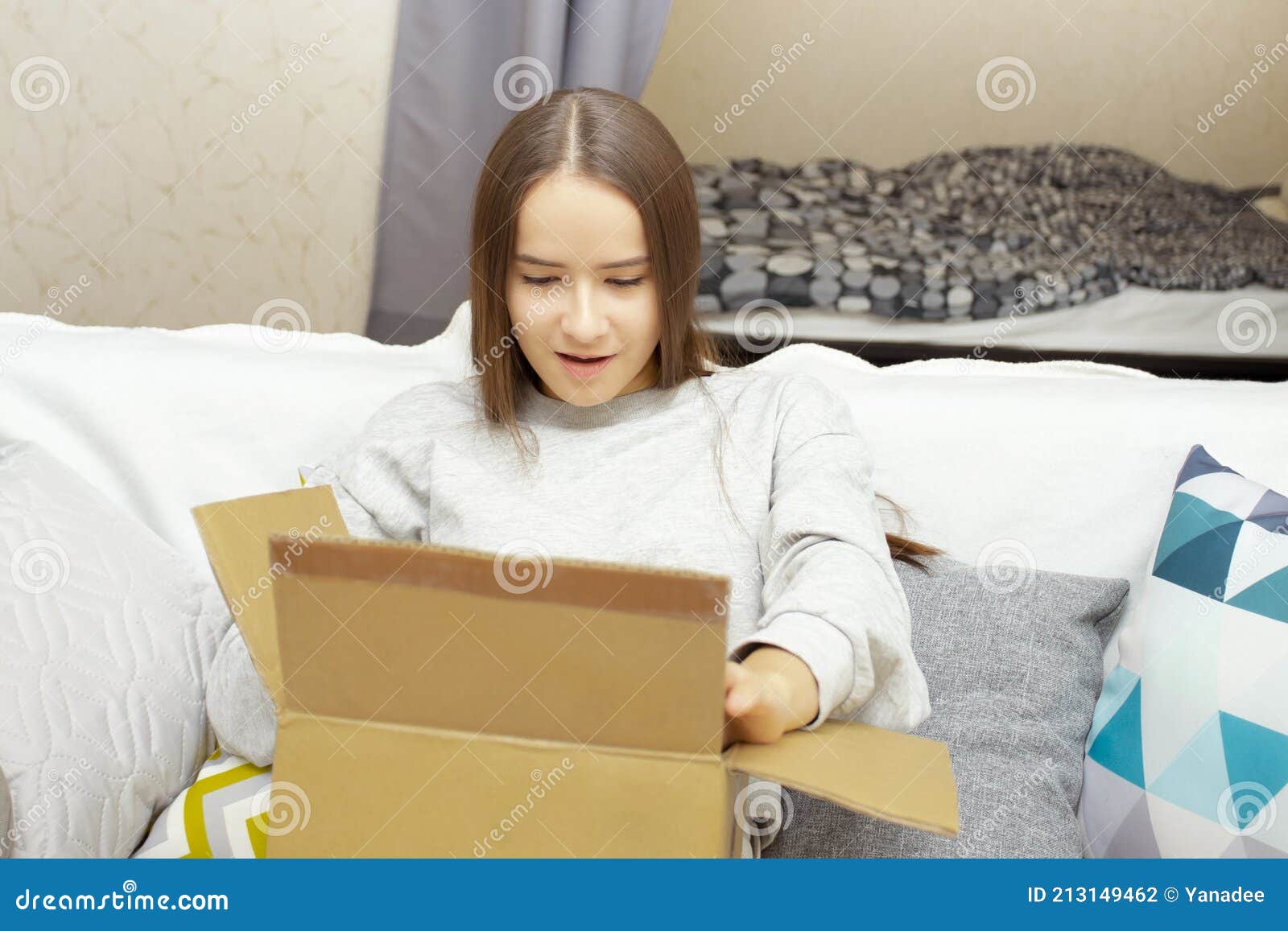 A Young Woman Looks in Surprise at a Box a Postal Parcel Stock Photo ...