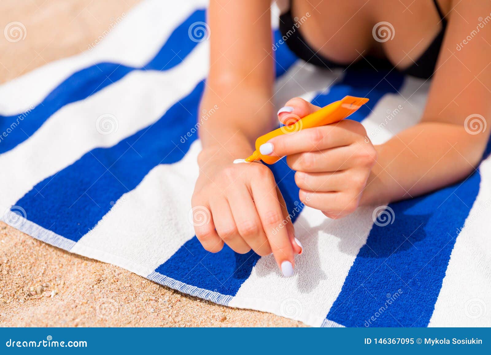 Young Woman Is Lying On Striped Towel On The Sand At The Beach And