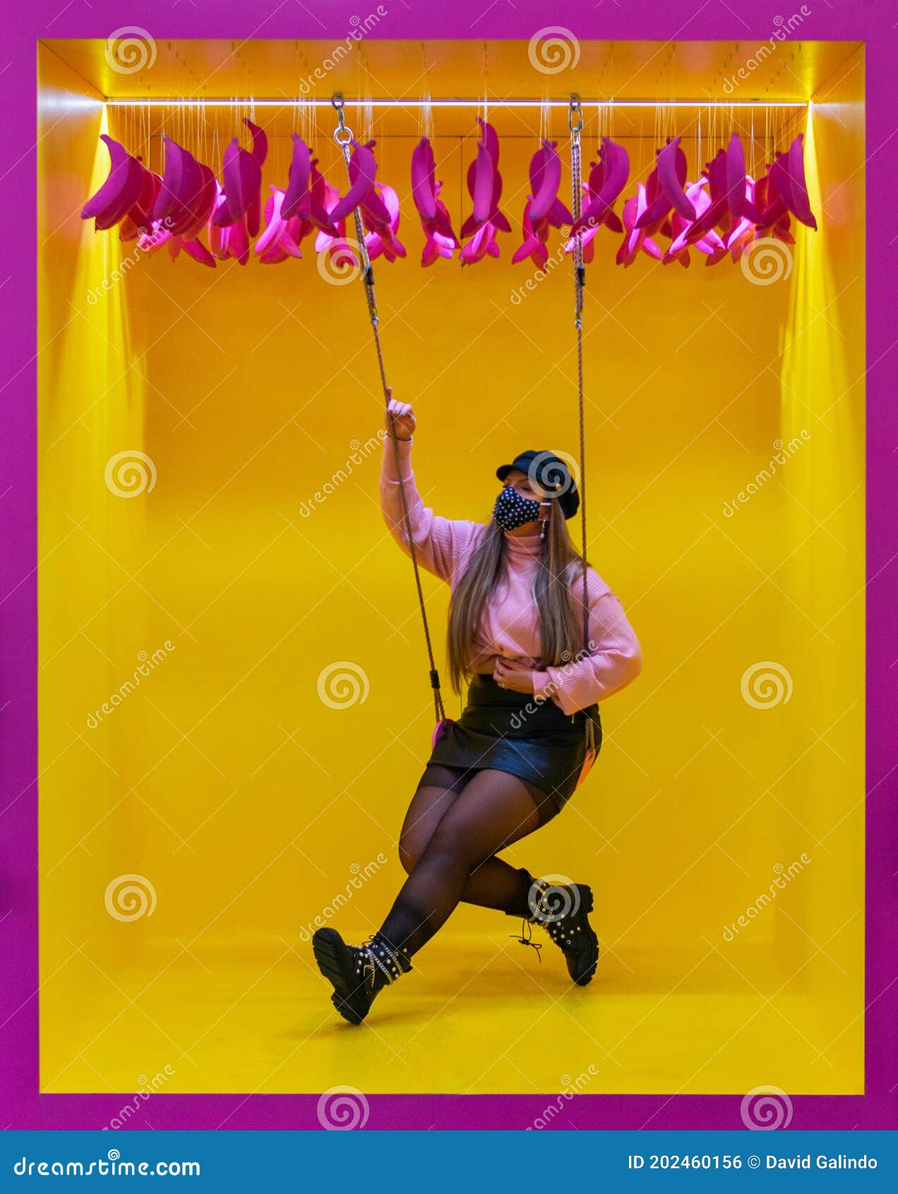 Young Woman with Mask on Swing with Yellow Background Stock Photo ...