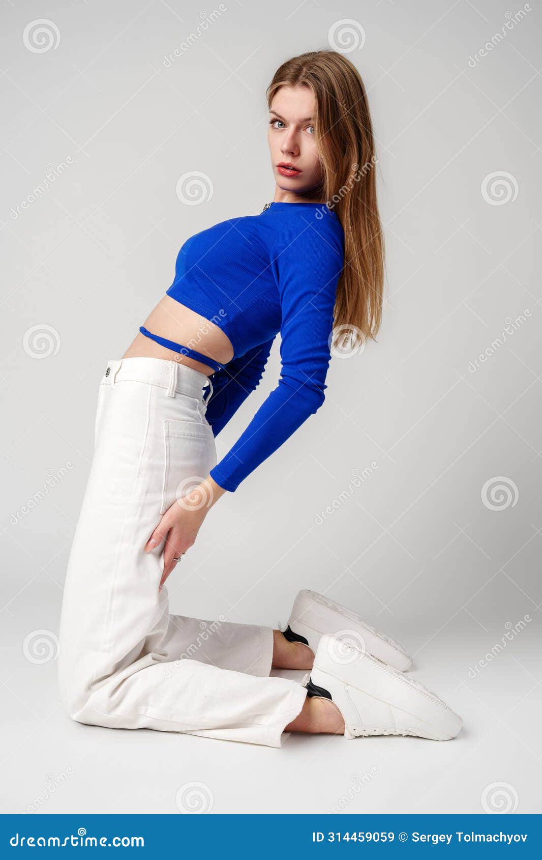 Young Woman Model in Blue Top and White Pants Posing on White ...