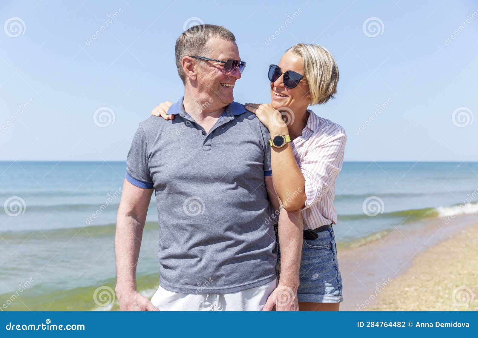 A Young Woman And An Older Man Are Laughing And Hugging On The Seashore