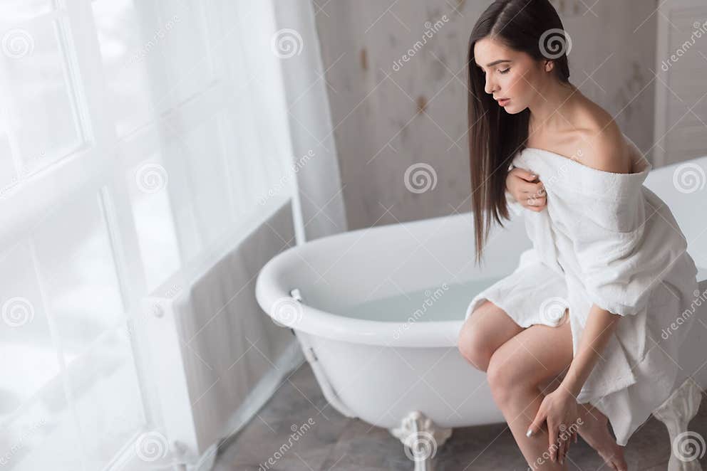 Young Woman Partially Dressed In Robe Taking Care Of Her Legs After