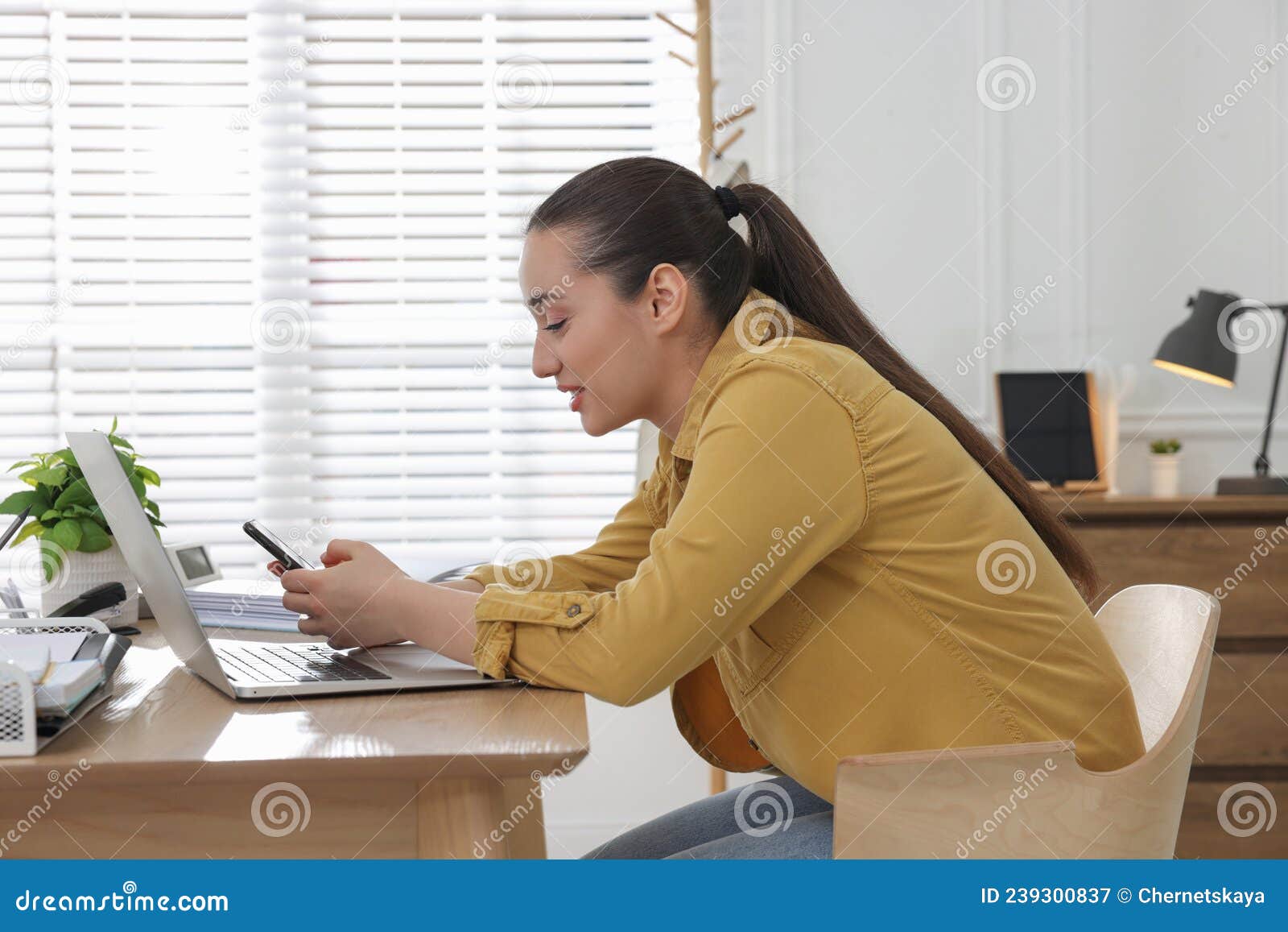 Young Woman with Poor Posture Using Smartphone at Table Indoors Stock ...