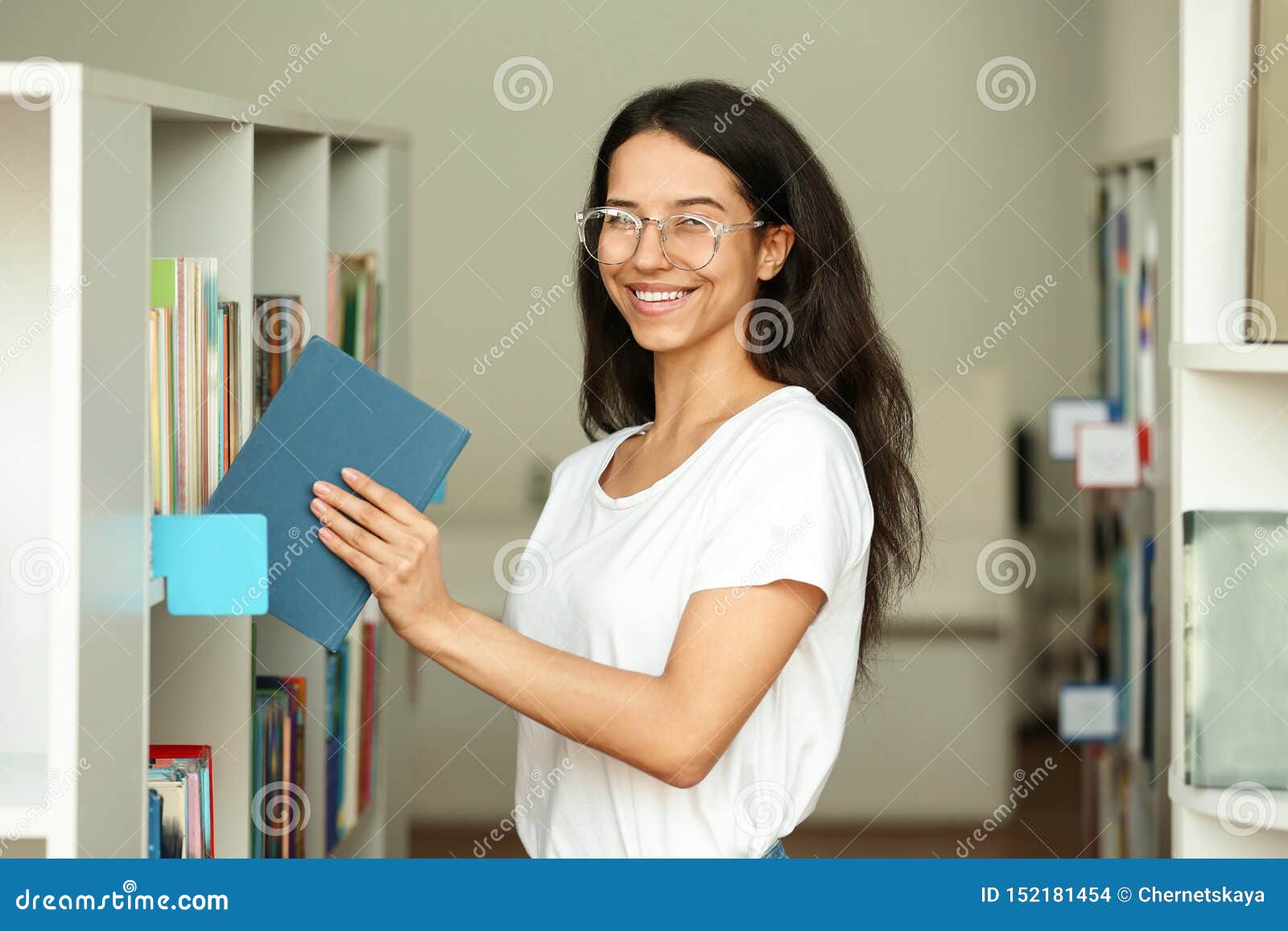 Young Woman Putting Book on Shelf Stock Photo - Image of library ...