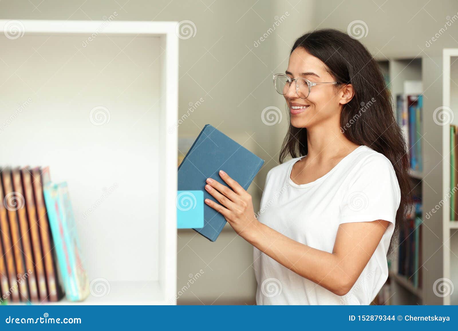 Young Woman Putting Book on Shelf Stock Photo - Image of books ...