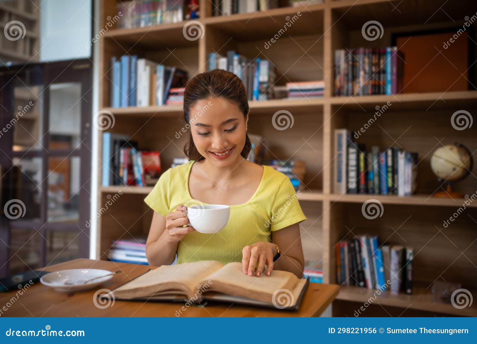 Young Woman Reading Book And Drink Hot Coffee In Library At Home