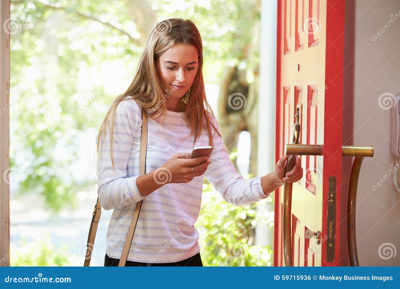 Young Woman Returning Home for Work Looking at Mobile Phone Stock Photo ...