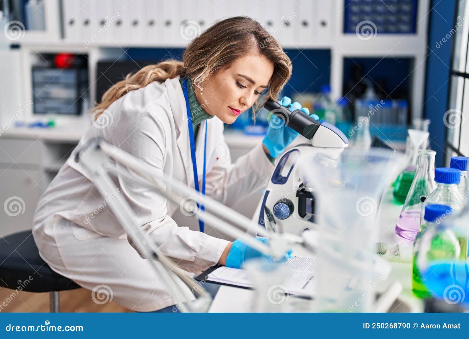 Young Woman Scientist Using Microscope Writing Report at Laboratory ...