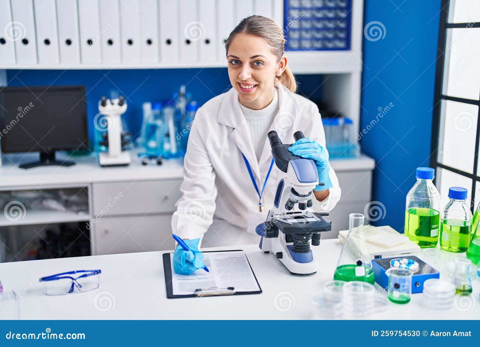 Young Woman Scientist Using Microscope Writing on Report at Laboratory ...