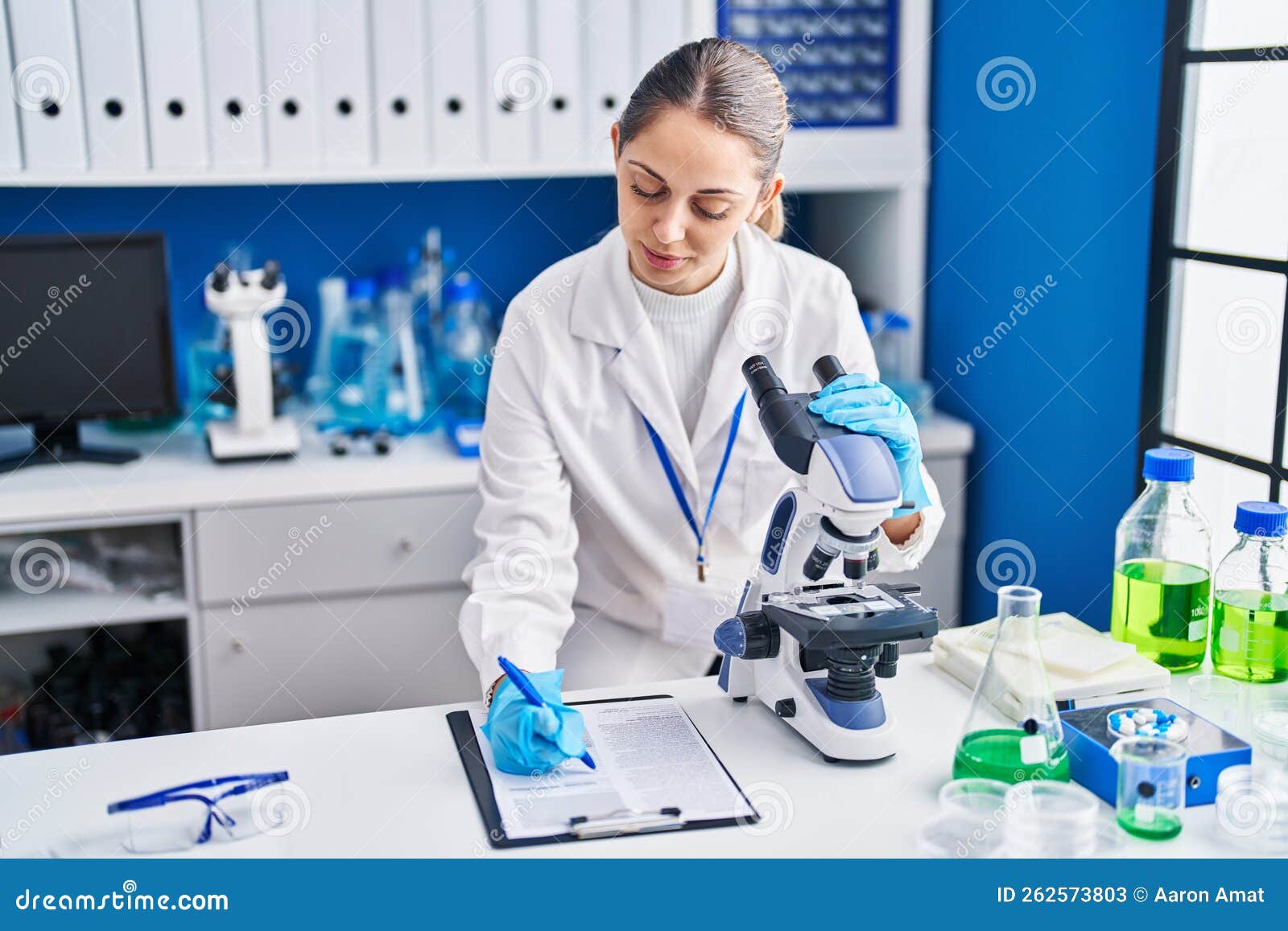 Young Woman Scientist Using Microscope Writing on Report at Laboratory ...