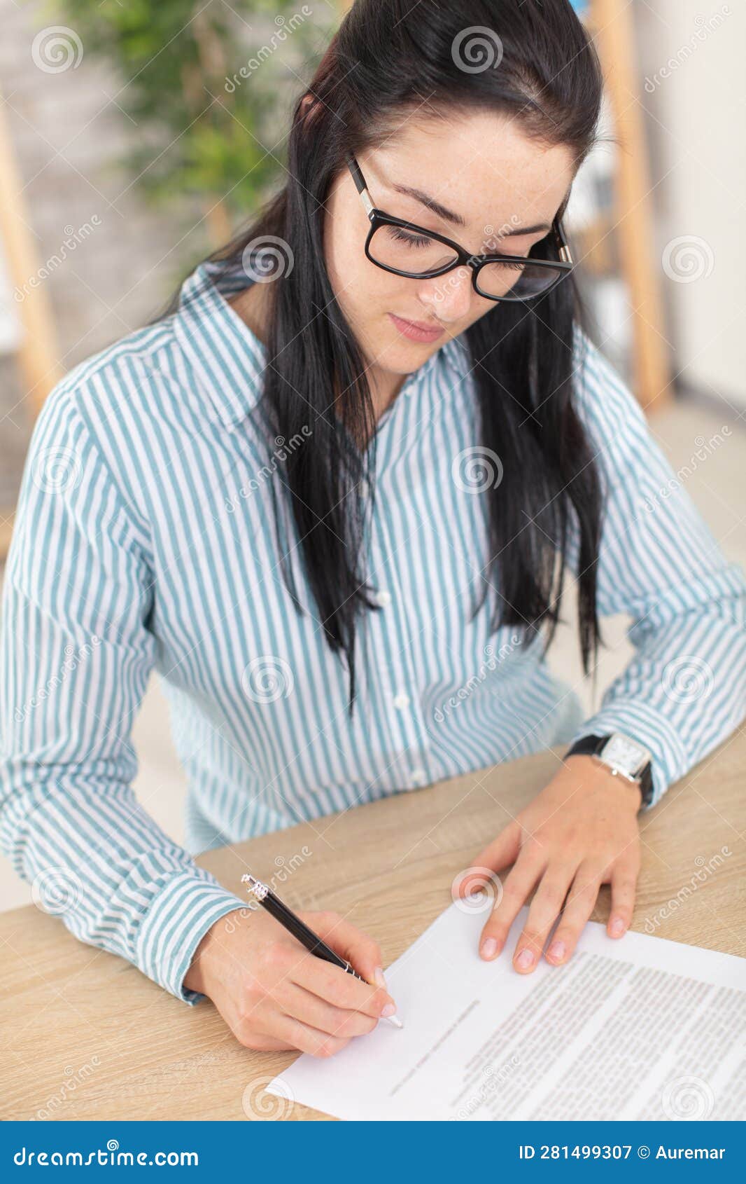 Young Woman Signing Document while Sitting at Desk Stock Image - Image ...