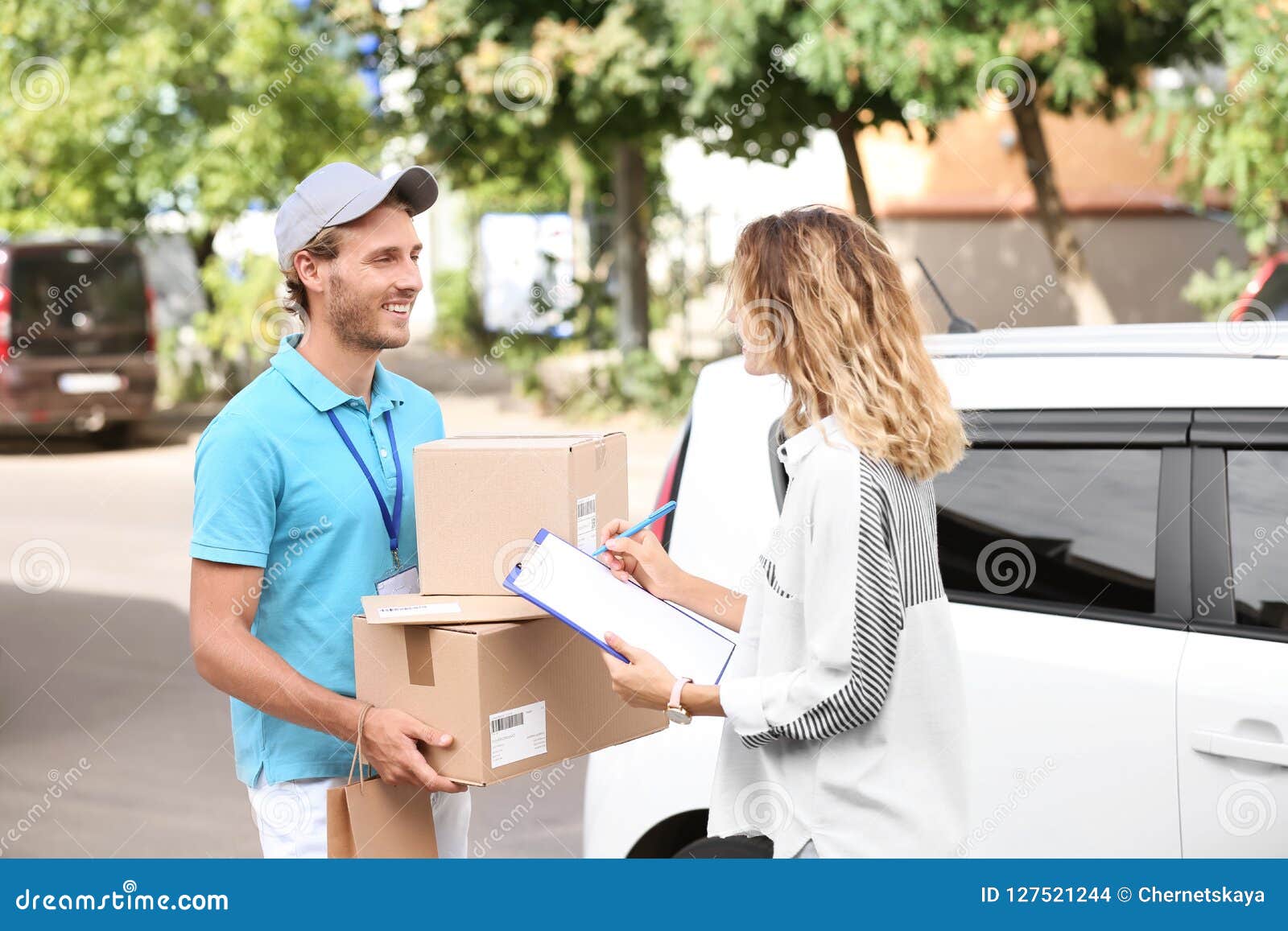 Young Woman Signing Documents after Receiving Parcels from Courier ...