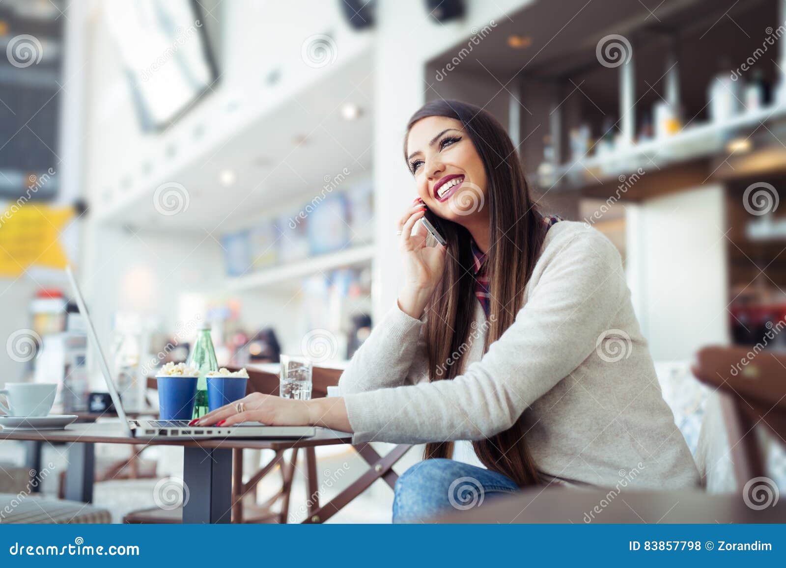 Young Woman Sitting in the Cafeteria with Laptop and Using Mobile Phone ...