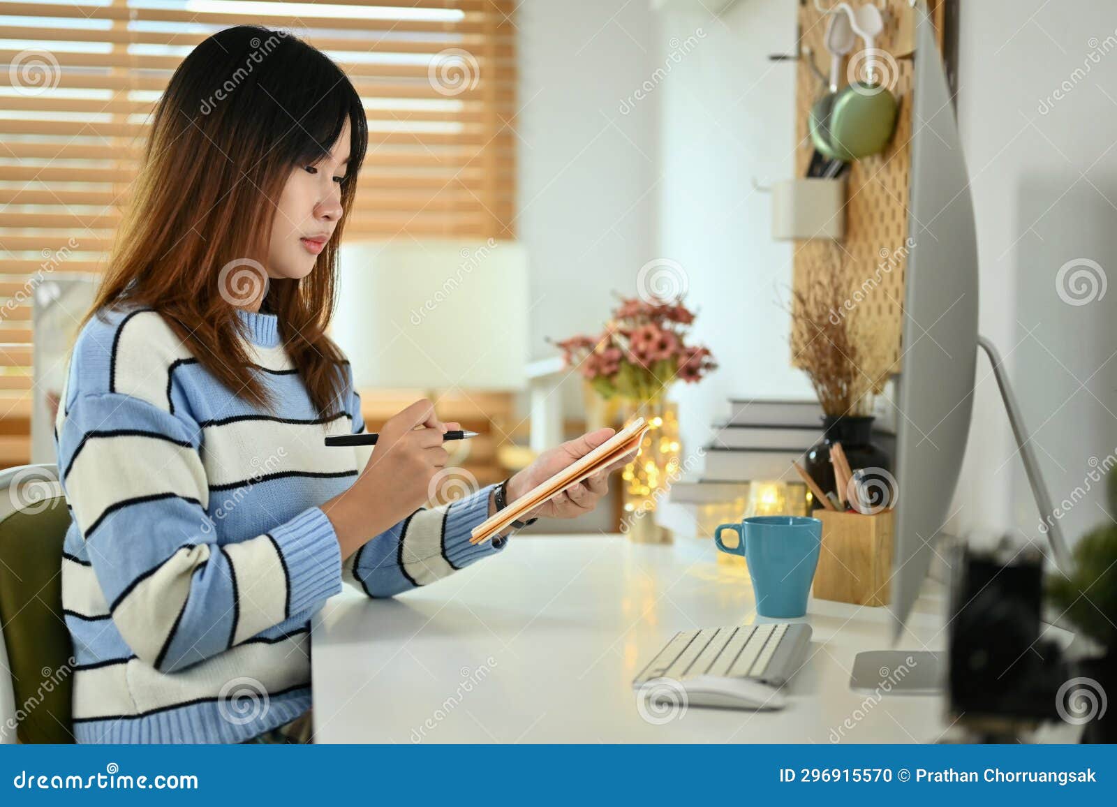Young Woman Sitting in Front of Computer Monitor and Writing Notes on ...