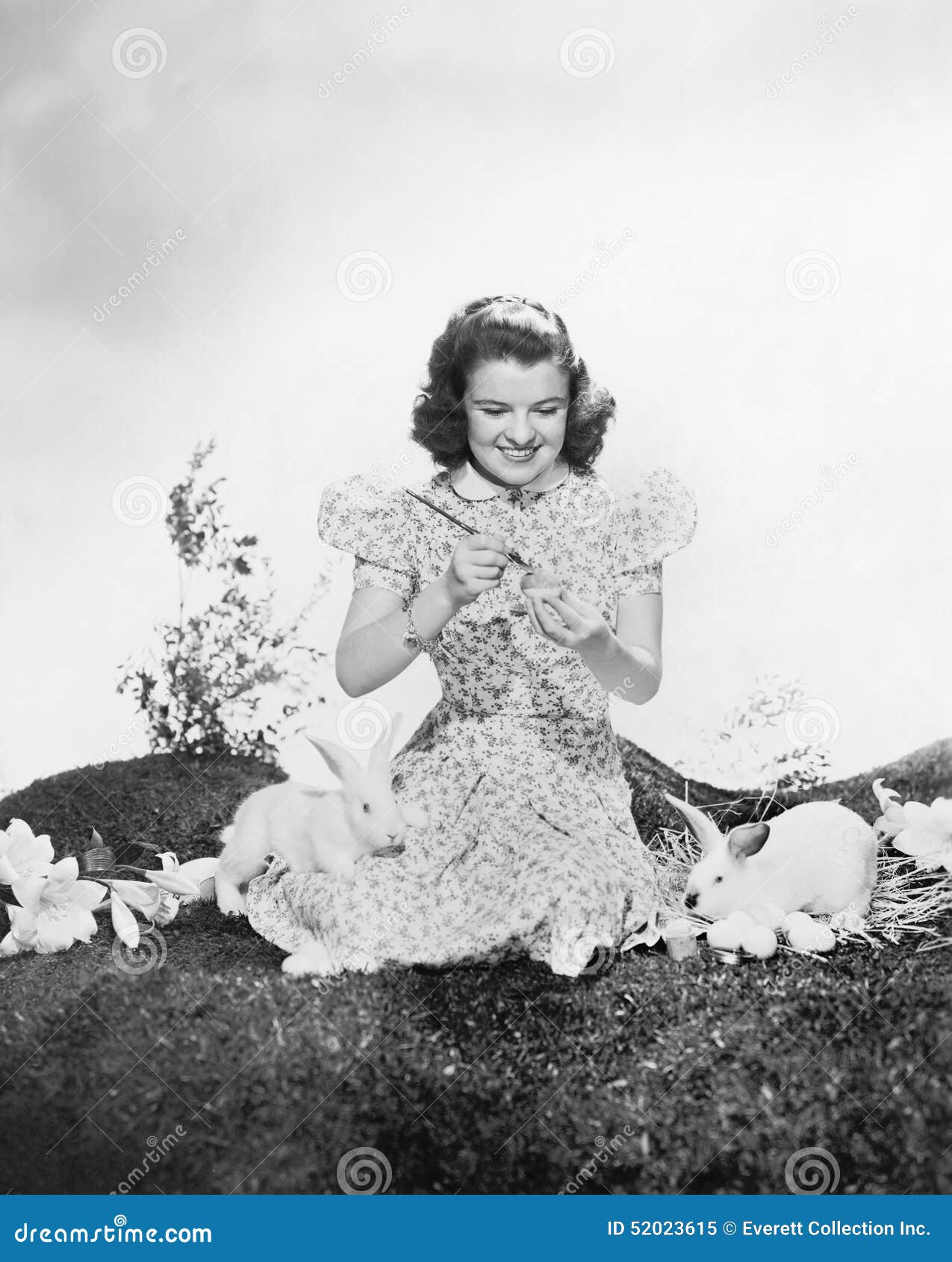 Young Woman Sitting on the Grass with Rabbits Painting an Easter Egg ...