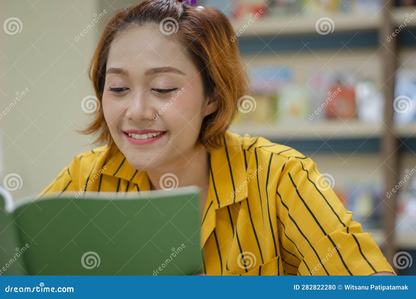 Young Woman Sitting Happily Reading a Book in the Library Stock Photo ...