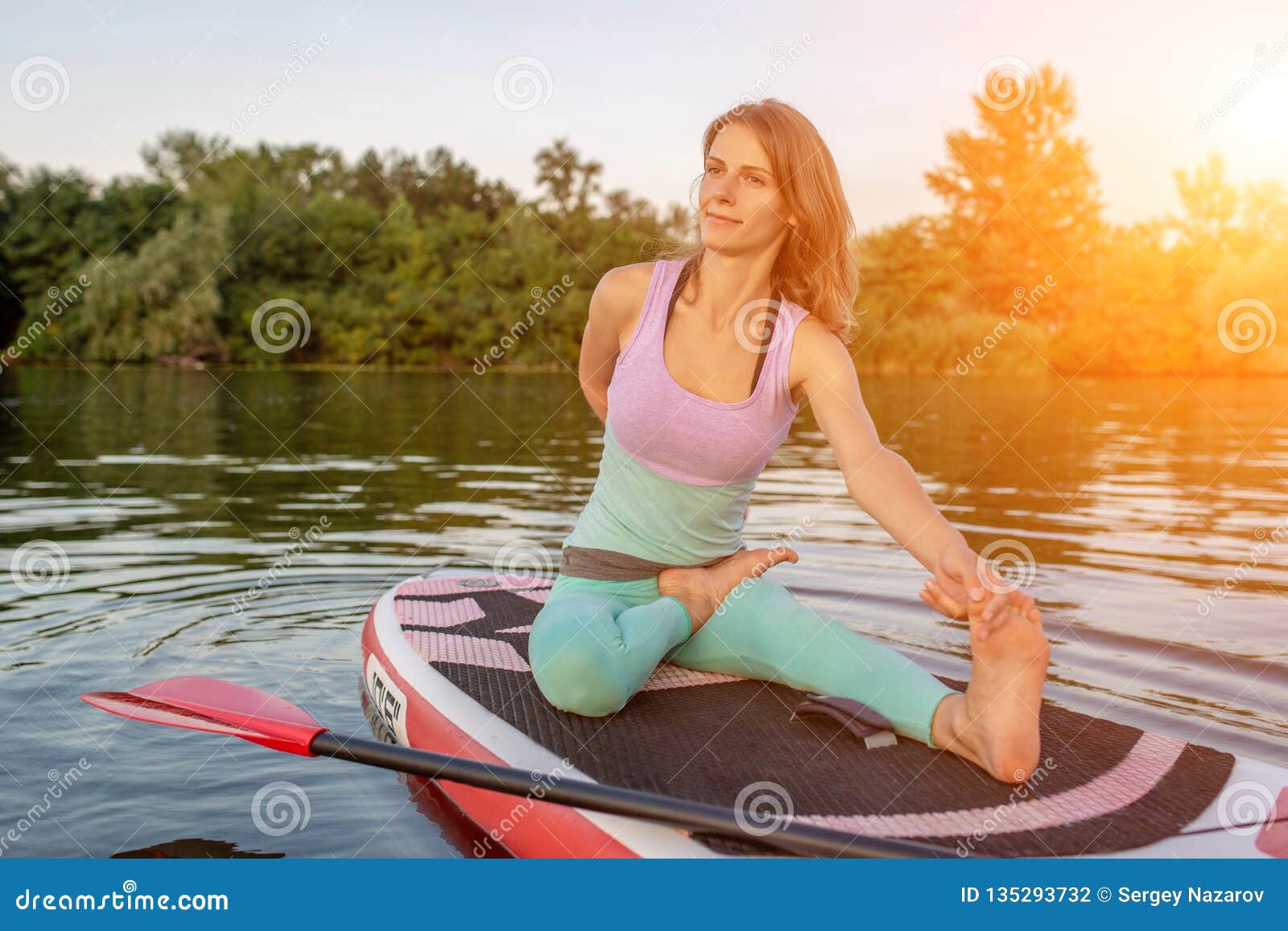 Young Woman Sitting on Paddle Board, Practicing Yoga Pose. Doing Yoga ...
