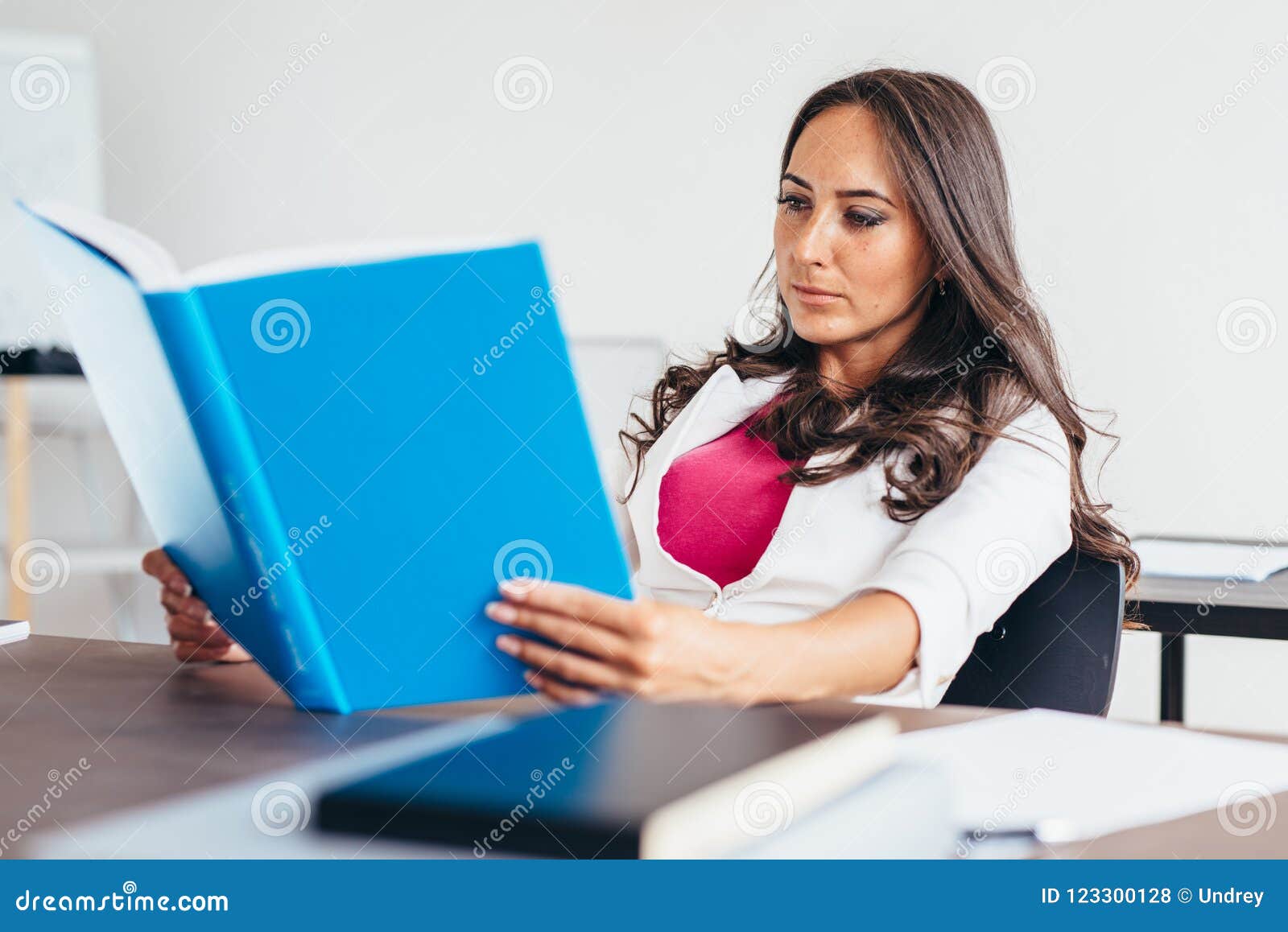 Young Woman Sitting by Table and Reading Book Stock Photo - Image of ...