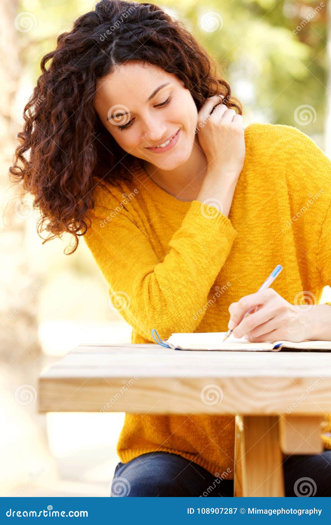 Young Woman Sitting at Table Writing in Book Stock Image - Image of ...