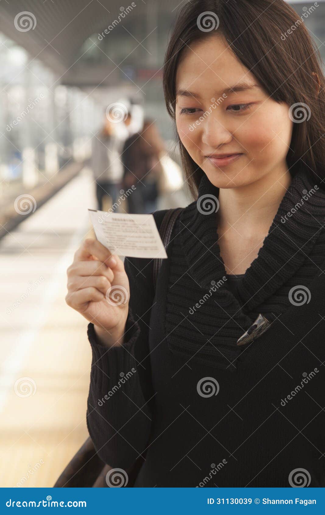 Young Woman Smiling and Looking at Train Ticket on Railroad Platform ...