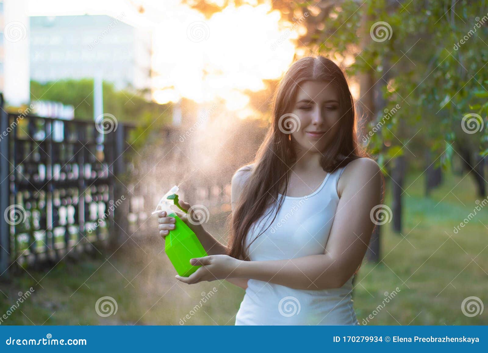 Young Woman Spraying Water on Herself from a Spray Bottle in a Summer ... Young Woman Spraying Water on Herself from a Spray Bottle in a Summer ...