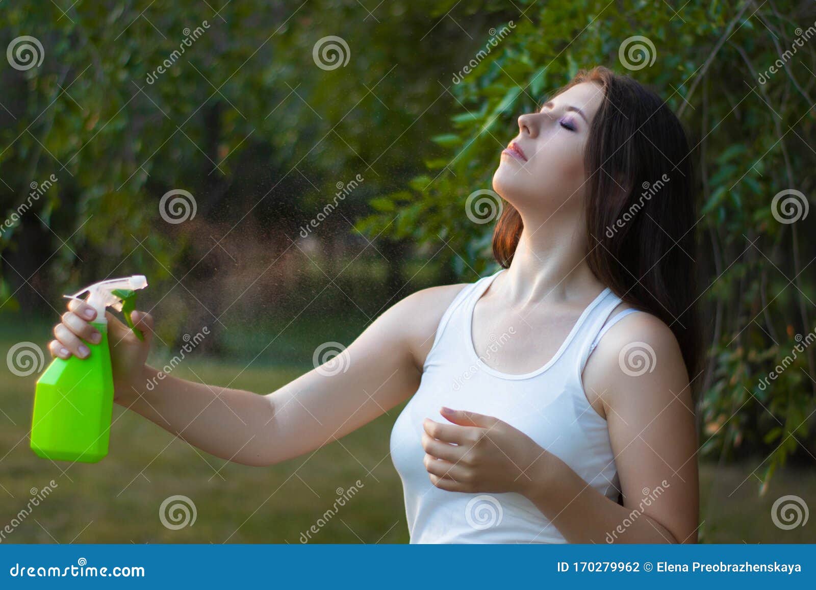 Young Woman Spraying Water on Herself from a Spray Bottle in a Summer ... Young Woman Spraying Water on Herself from a Spray Bottle in a Summer ...