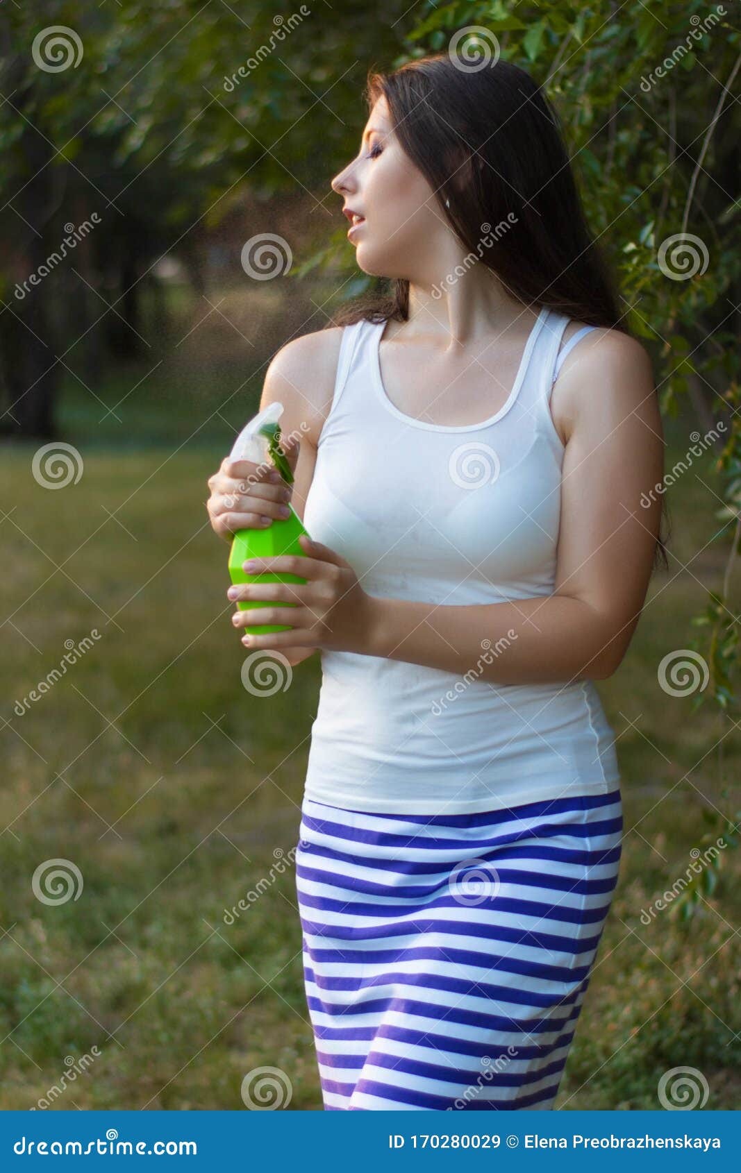 Young Woman Spraying Water on Herself from a Spray Bottle in a Summer ... Young Woman Spraying Water on Herself from a Spray Bottle in a Summer ...