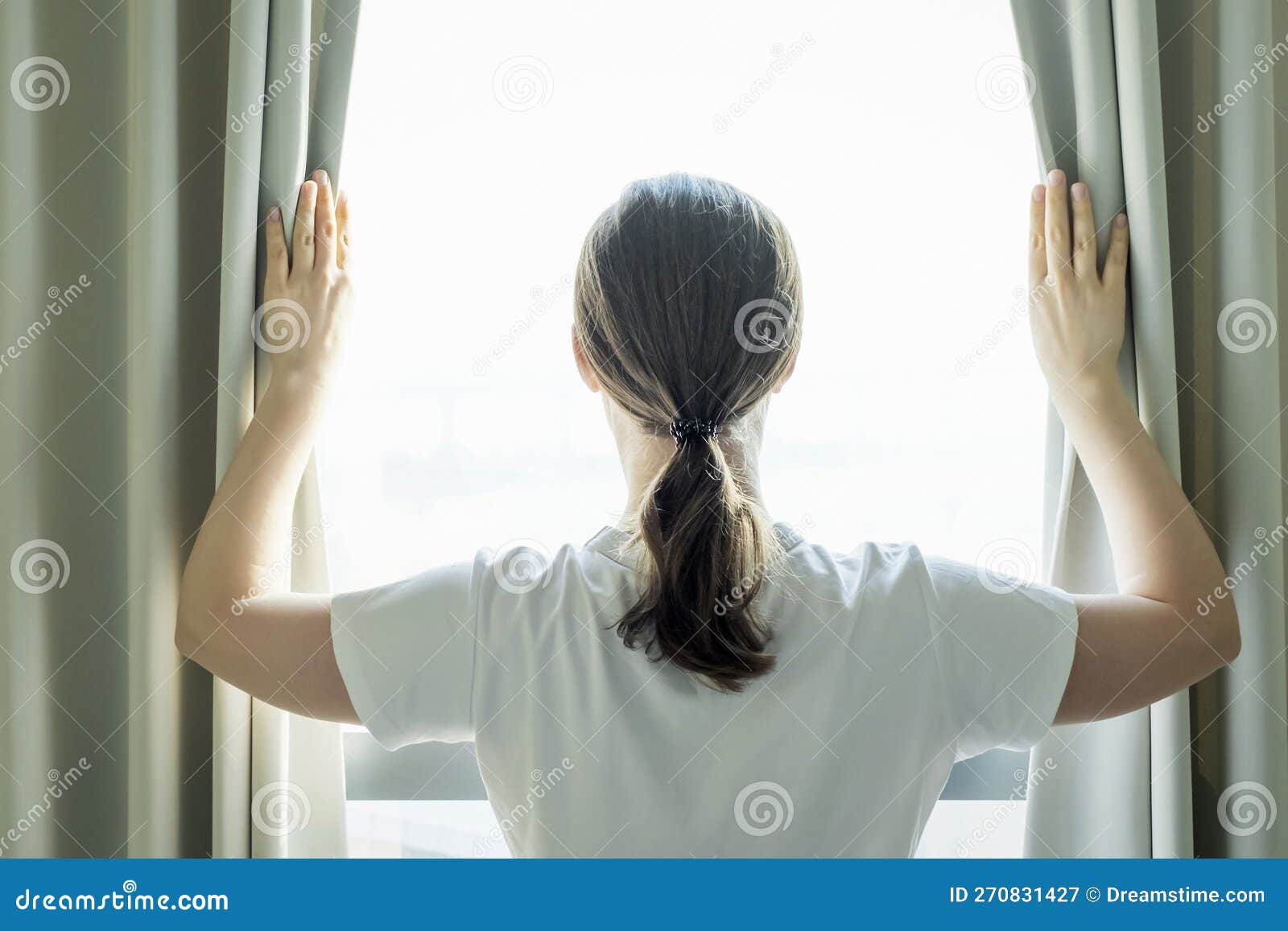Young Woman Stands at Window and Opens Curtains Back View. Stock Image ...