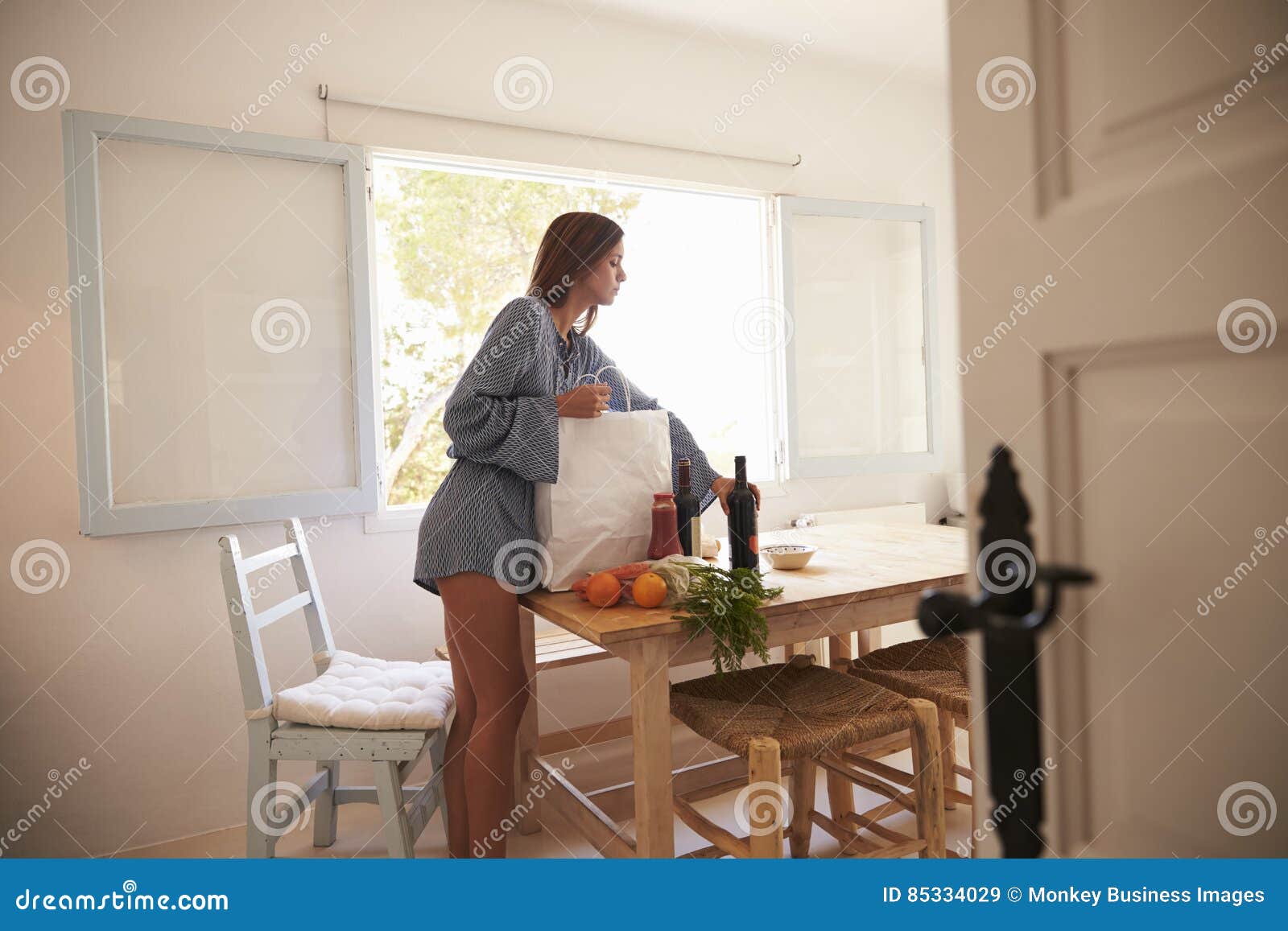 Young Woman Unpacking Shopping Bag on Kitchen Table Stock Image - Image ...
