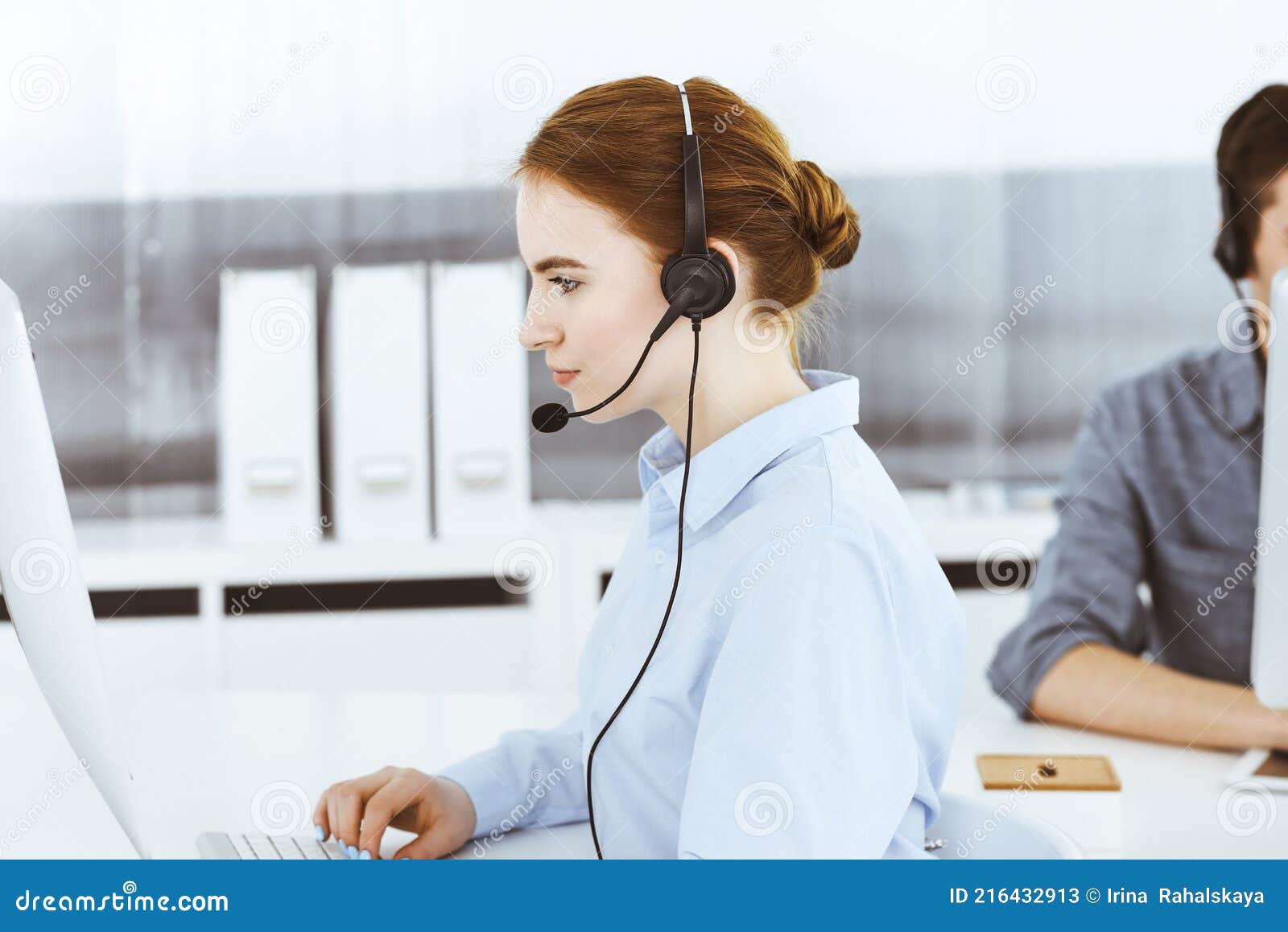 Young Woman Using Headset and Computer while Talking with Customers ...