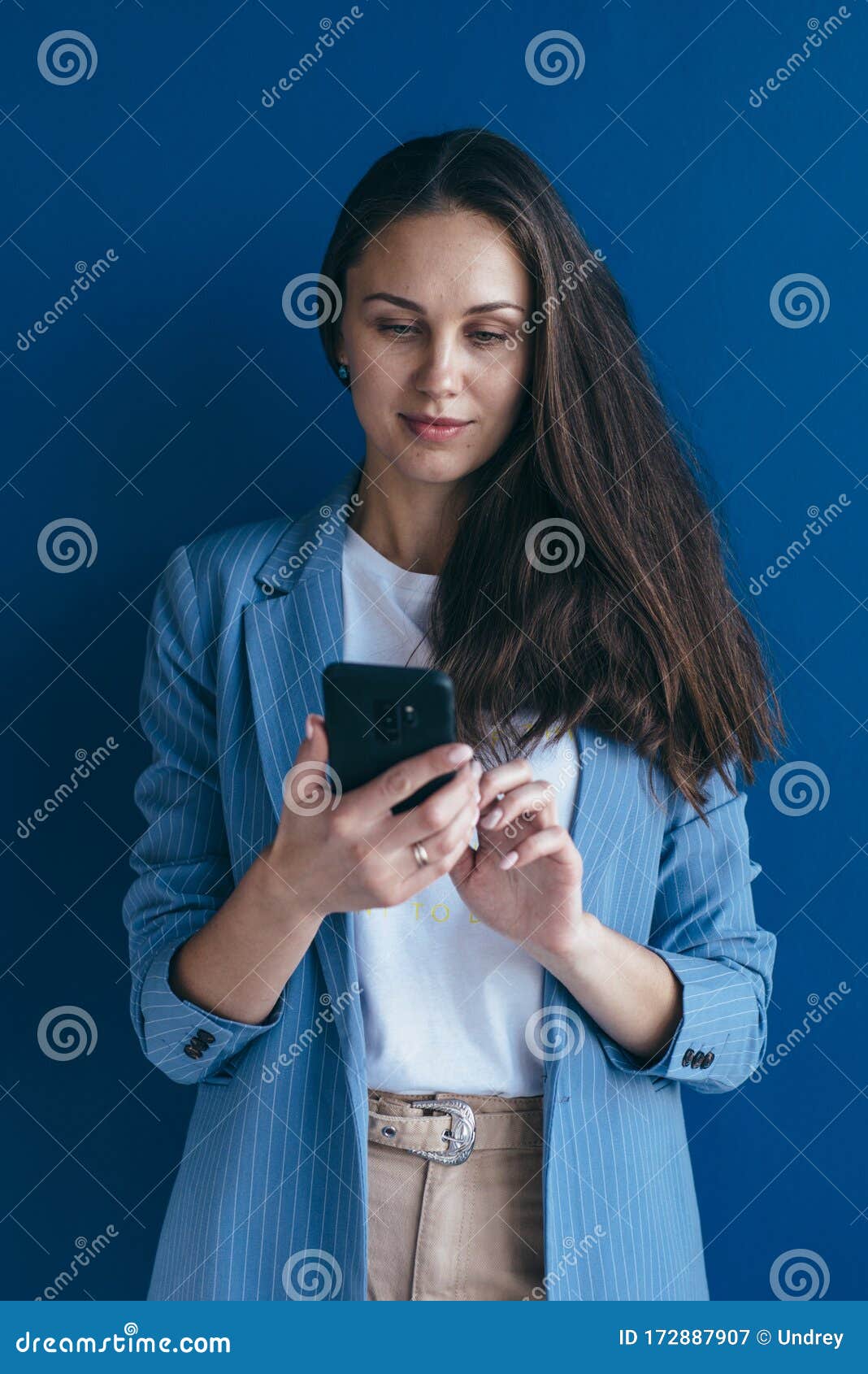 Young Woman Using Her Smart Phone Standing Against the Wall Stock Image ...